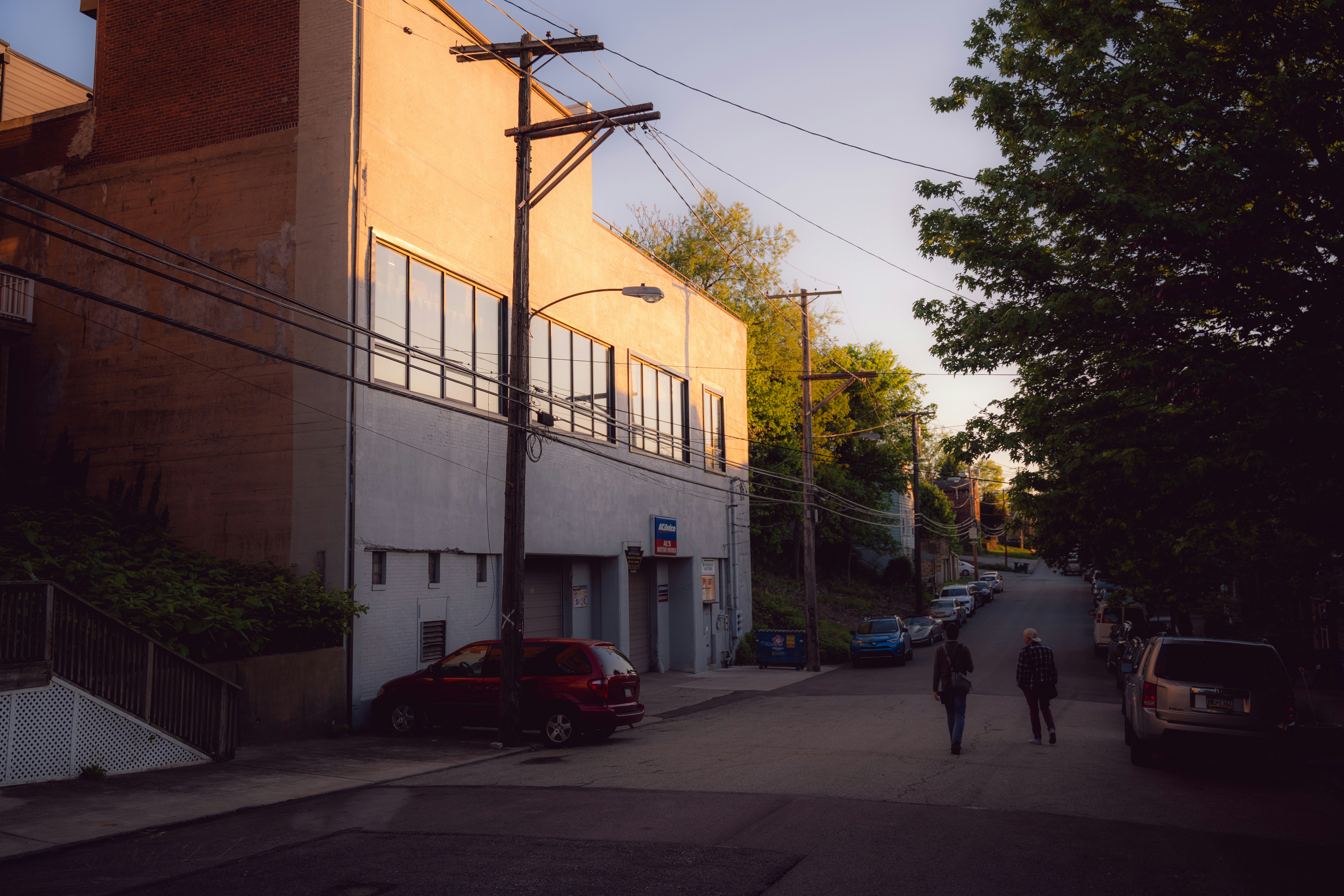 Twilight Street Down the Hill: Figures and Neon Sign in Dusk