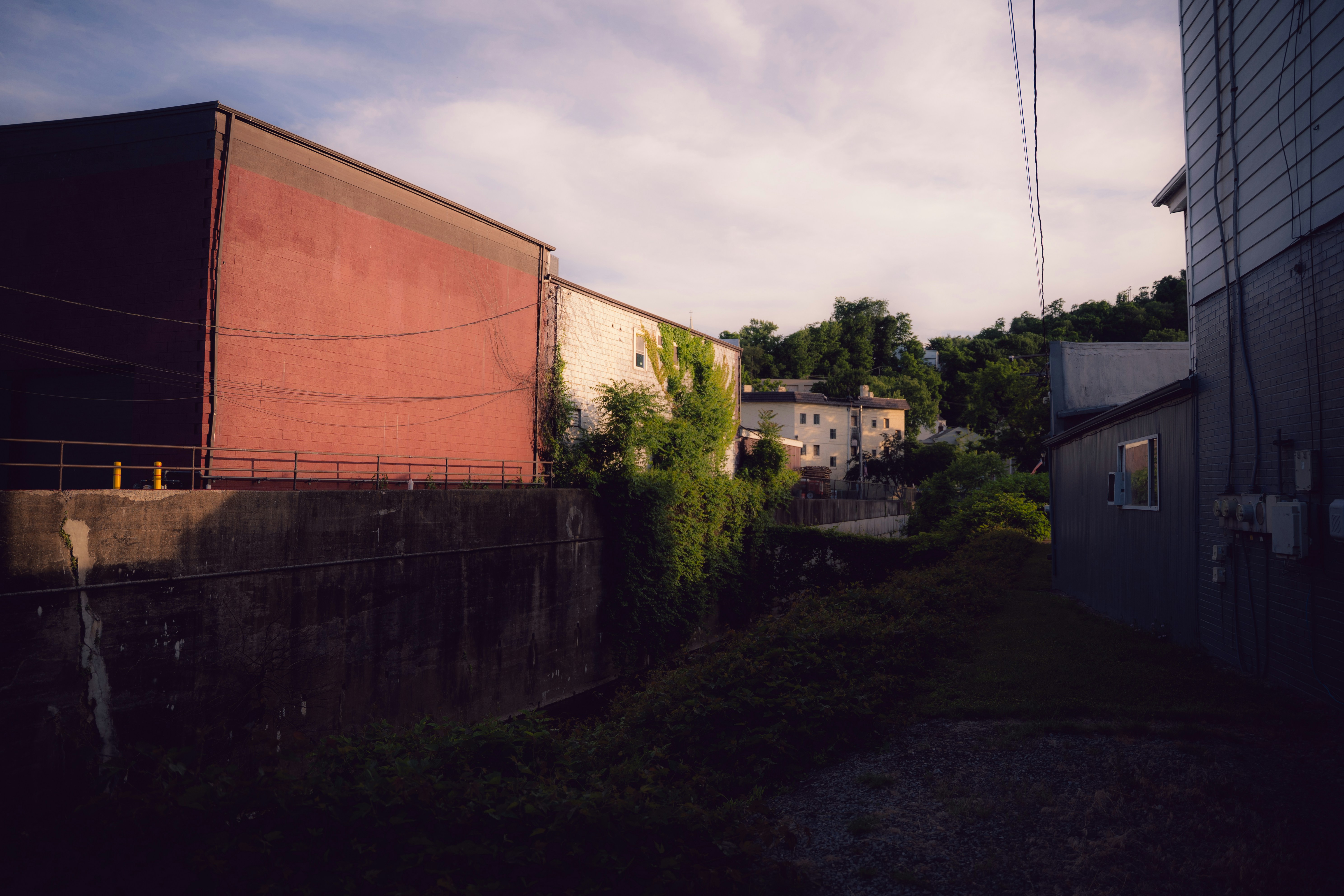 Sunlit alleyway between aging brick and corrugated walls