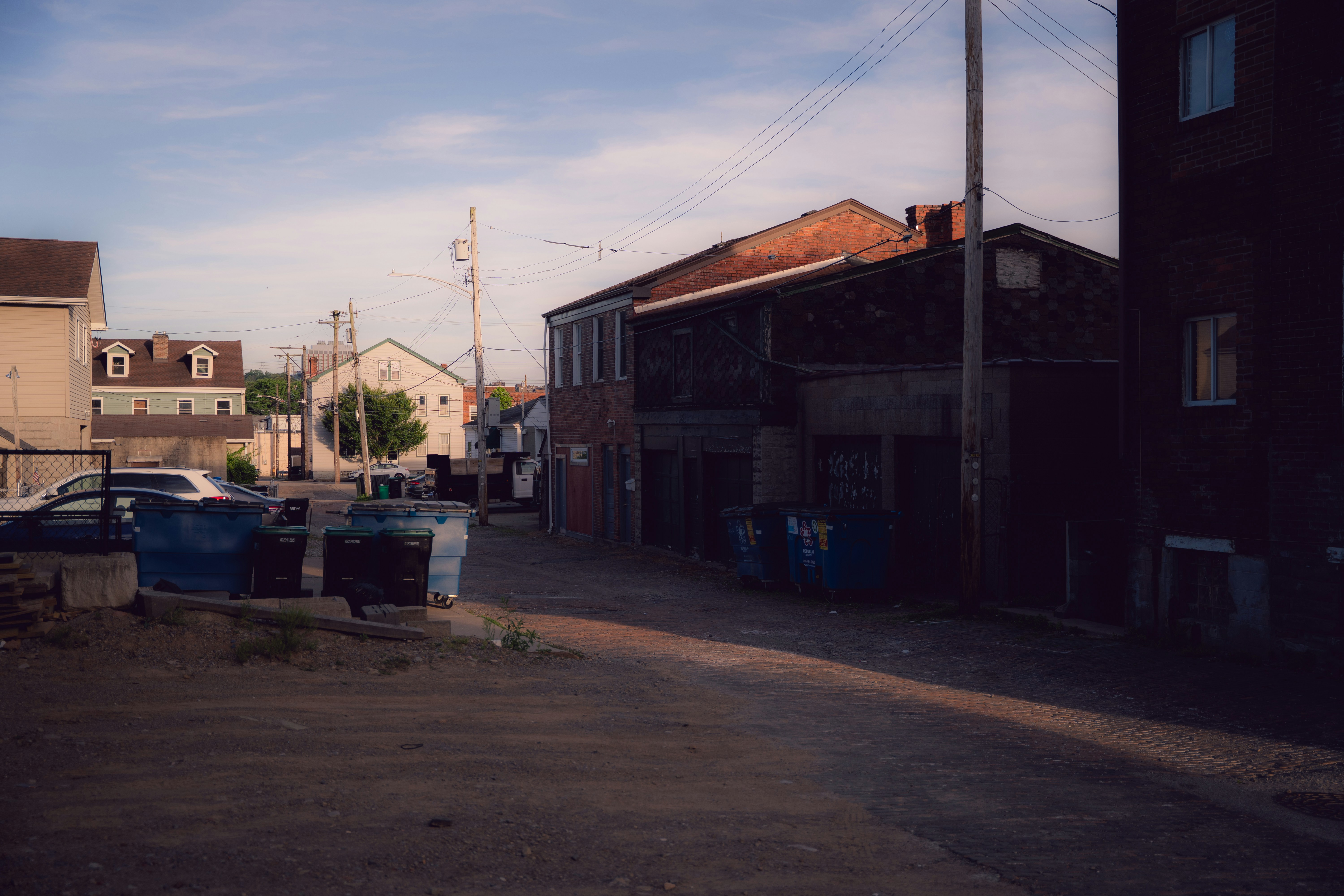 Sunlit Backstreet: A Quiet Alley Between Warehouses and Bins