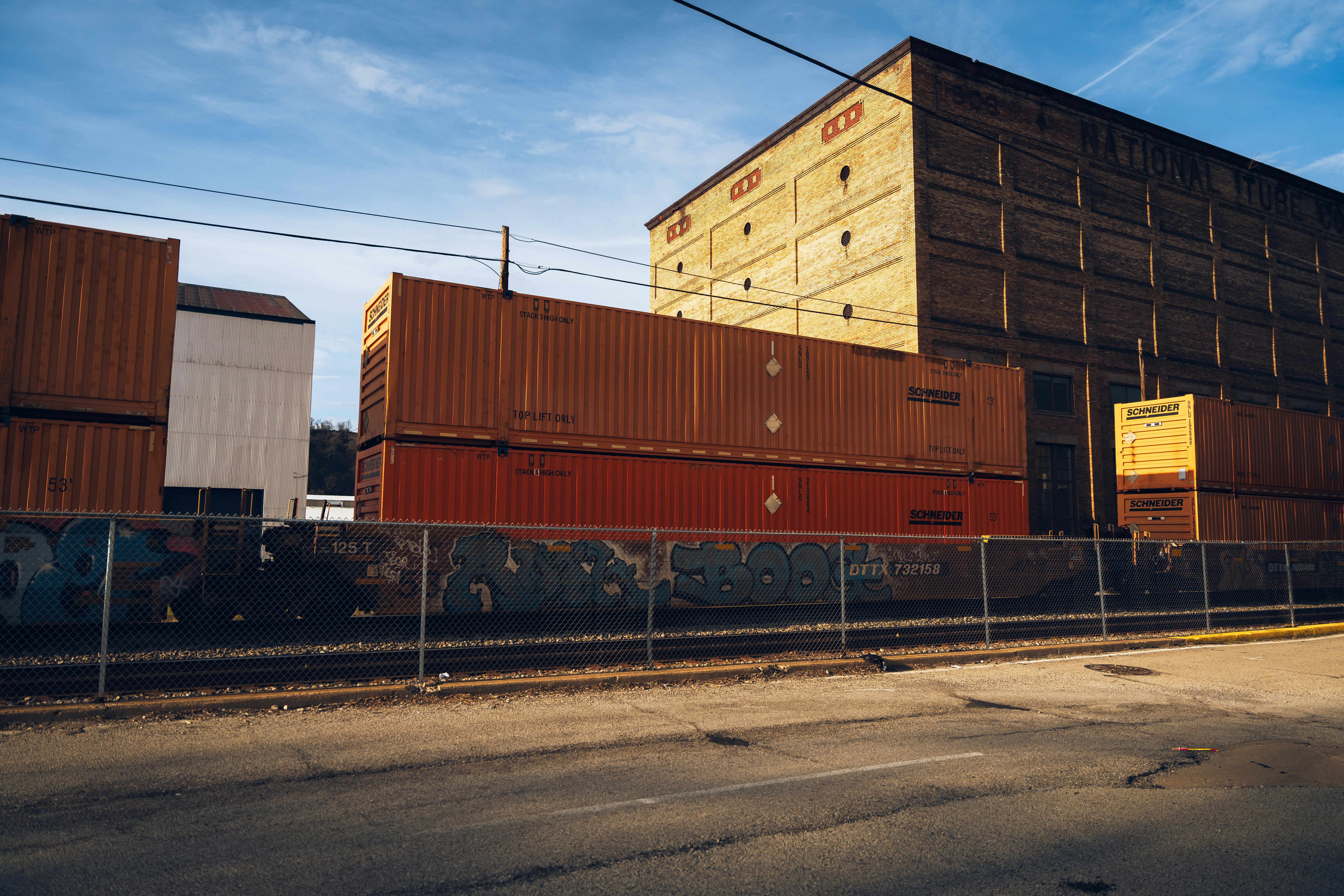 Containers and chain-link silhouette: late-afternoon industrial horizon