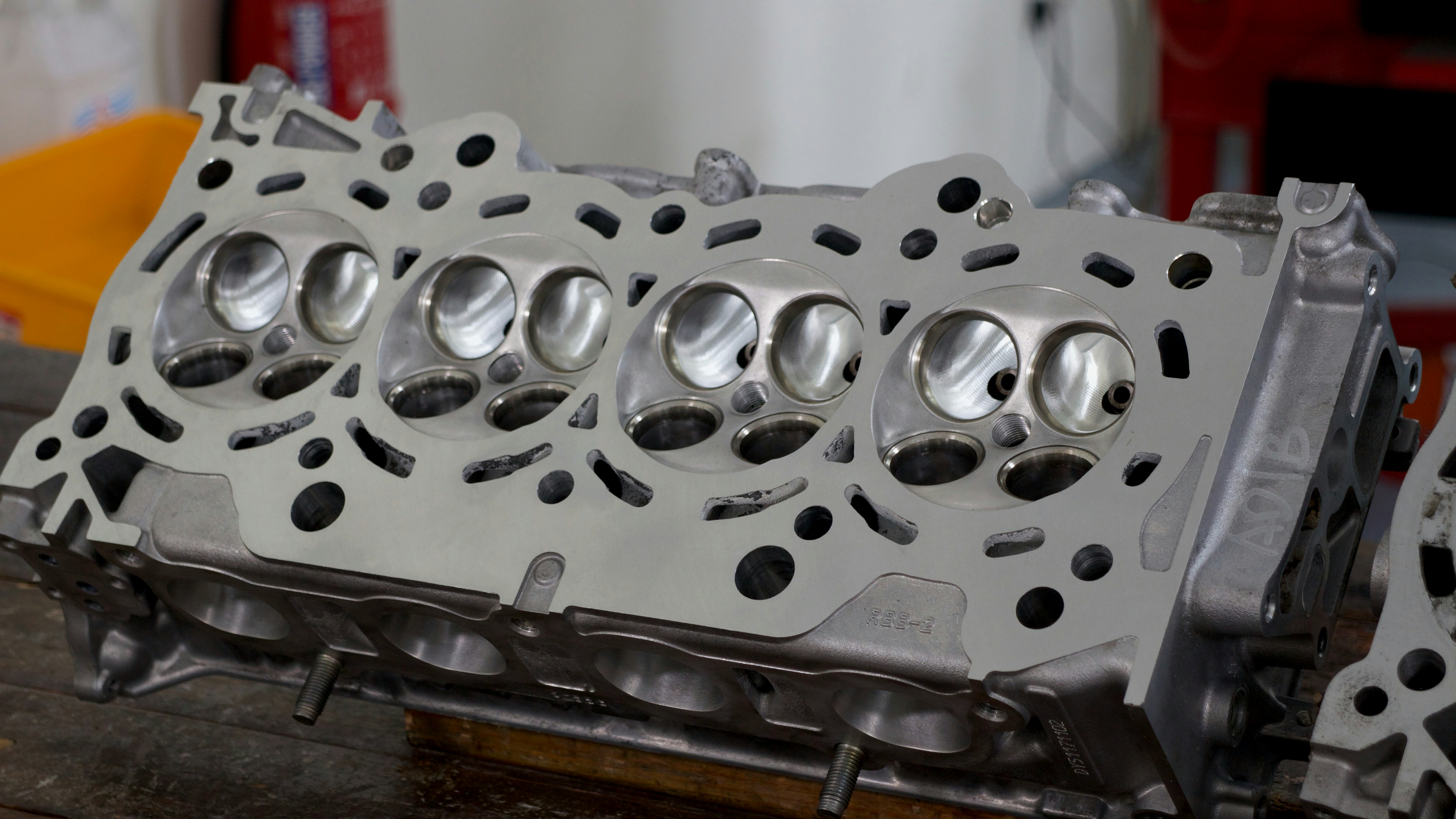 Close-up view of a high-performance engine cylinder head with polished valve cups and complex machining marks; industrial component showcased for mechanical detailing.