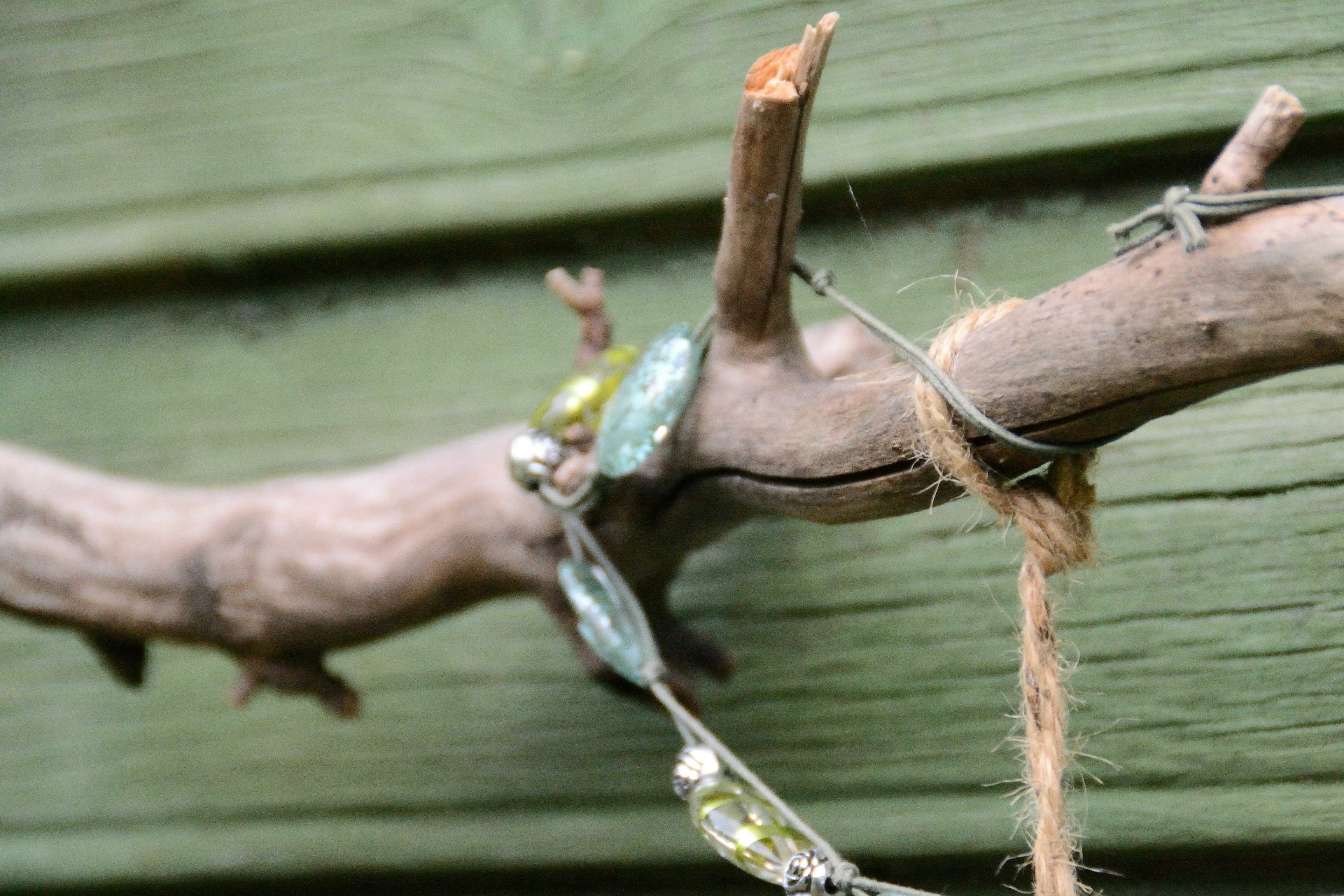 Weathered twine and glass beads on a mossy rail