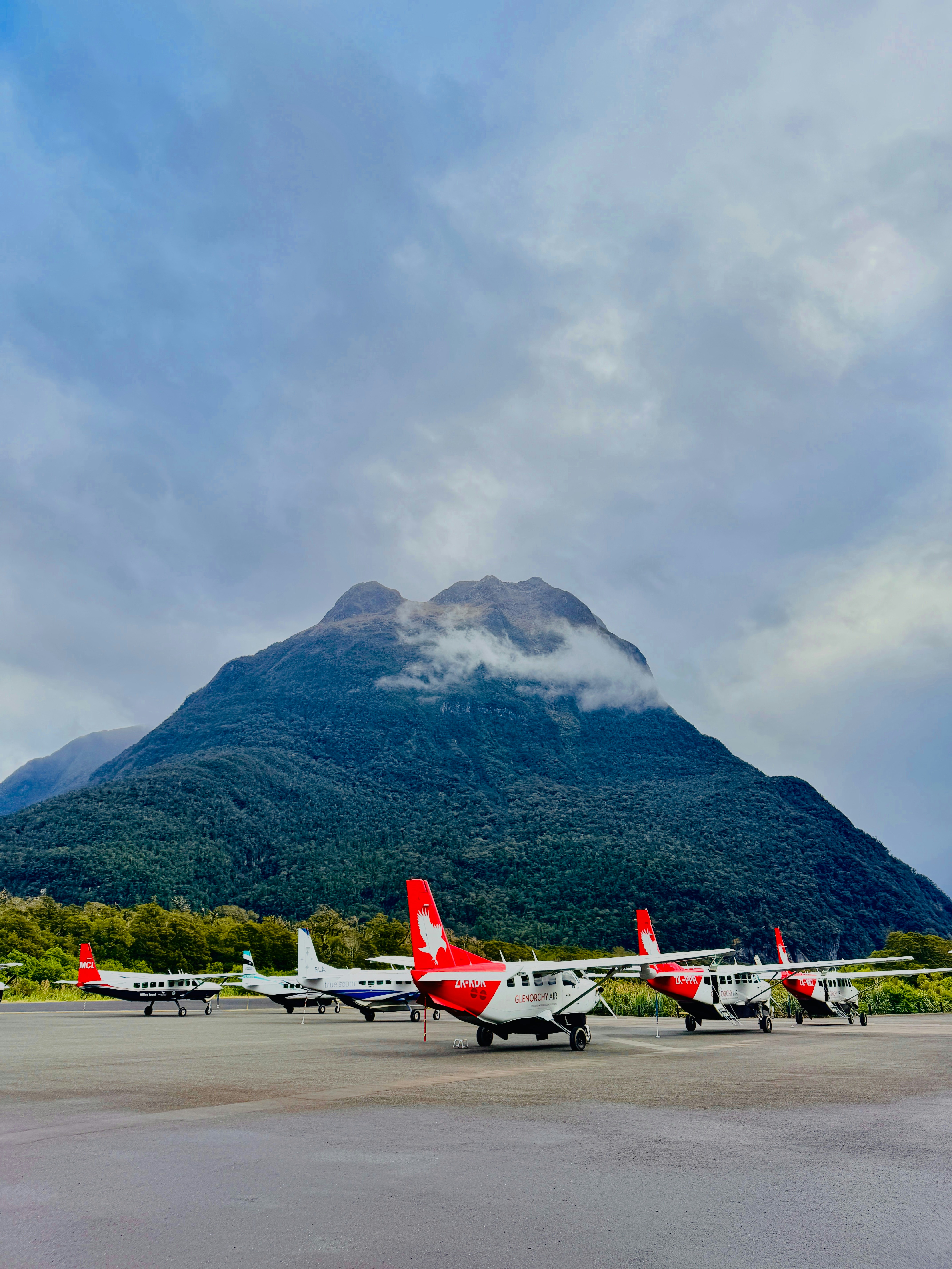 Mountainside Tarmac: A Row of Red-Trimmed Planes at Dawn