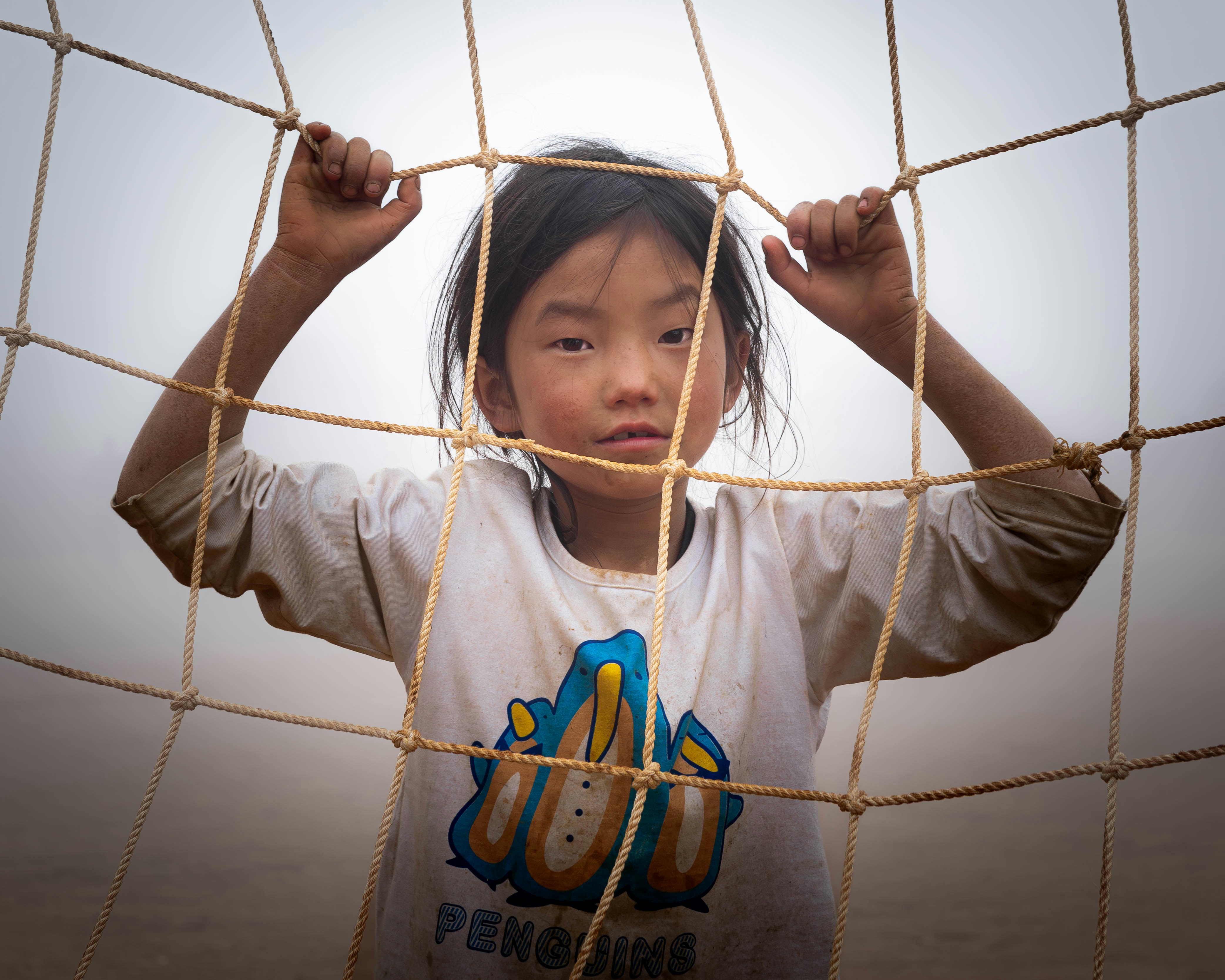 Child at the Net: Focused Gaze through Rope Grid