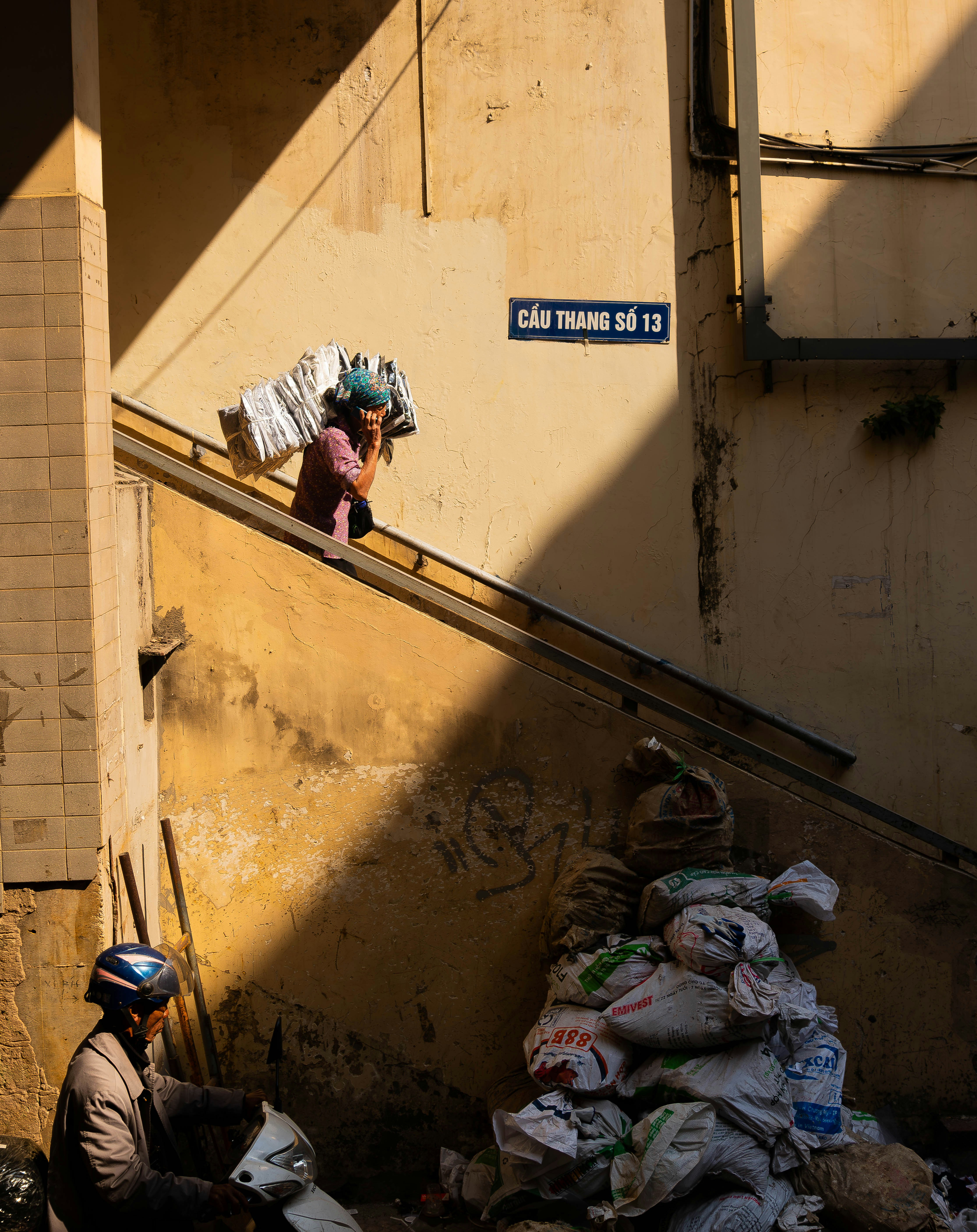 Sunlit Stairs: A Luggage of Labor on a Warming Wall