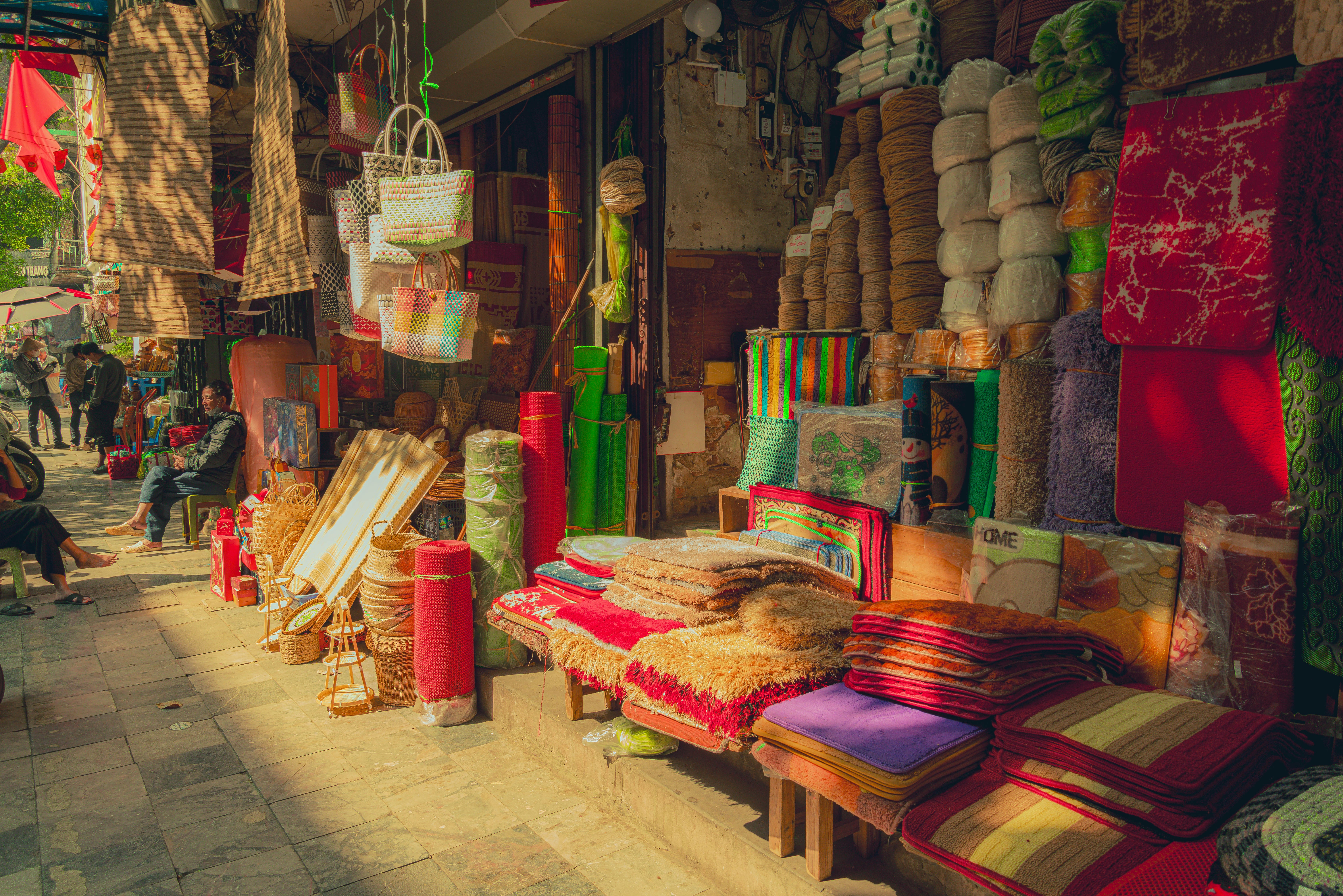 Sunlit Textile Bazaar: Colorful Cushions and Straw Mats in a Lively Alley