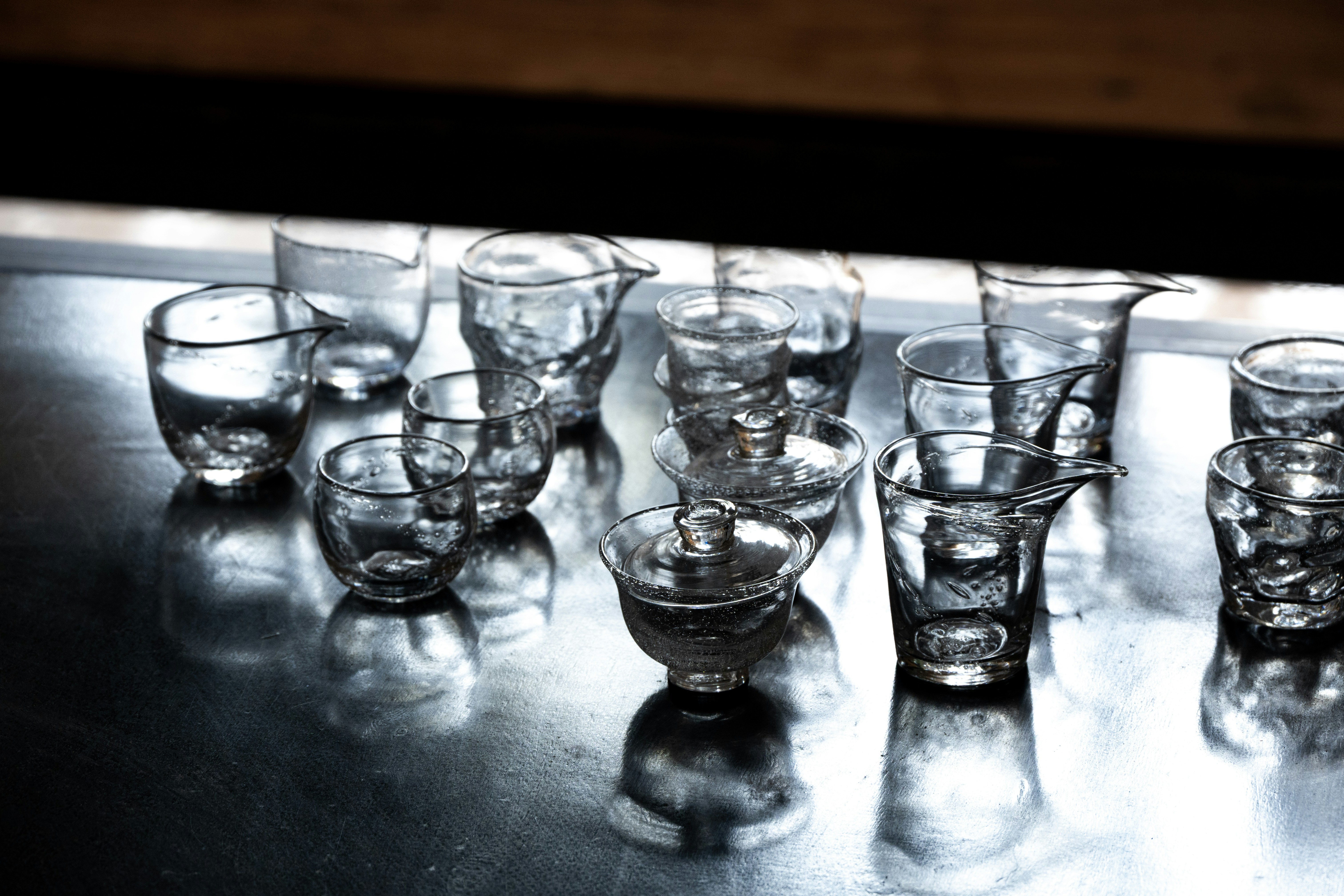 Glassy Tides: An Array of Night-Blue Glassware on a Reflective Surface
