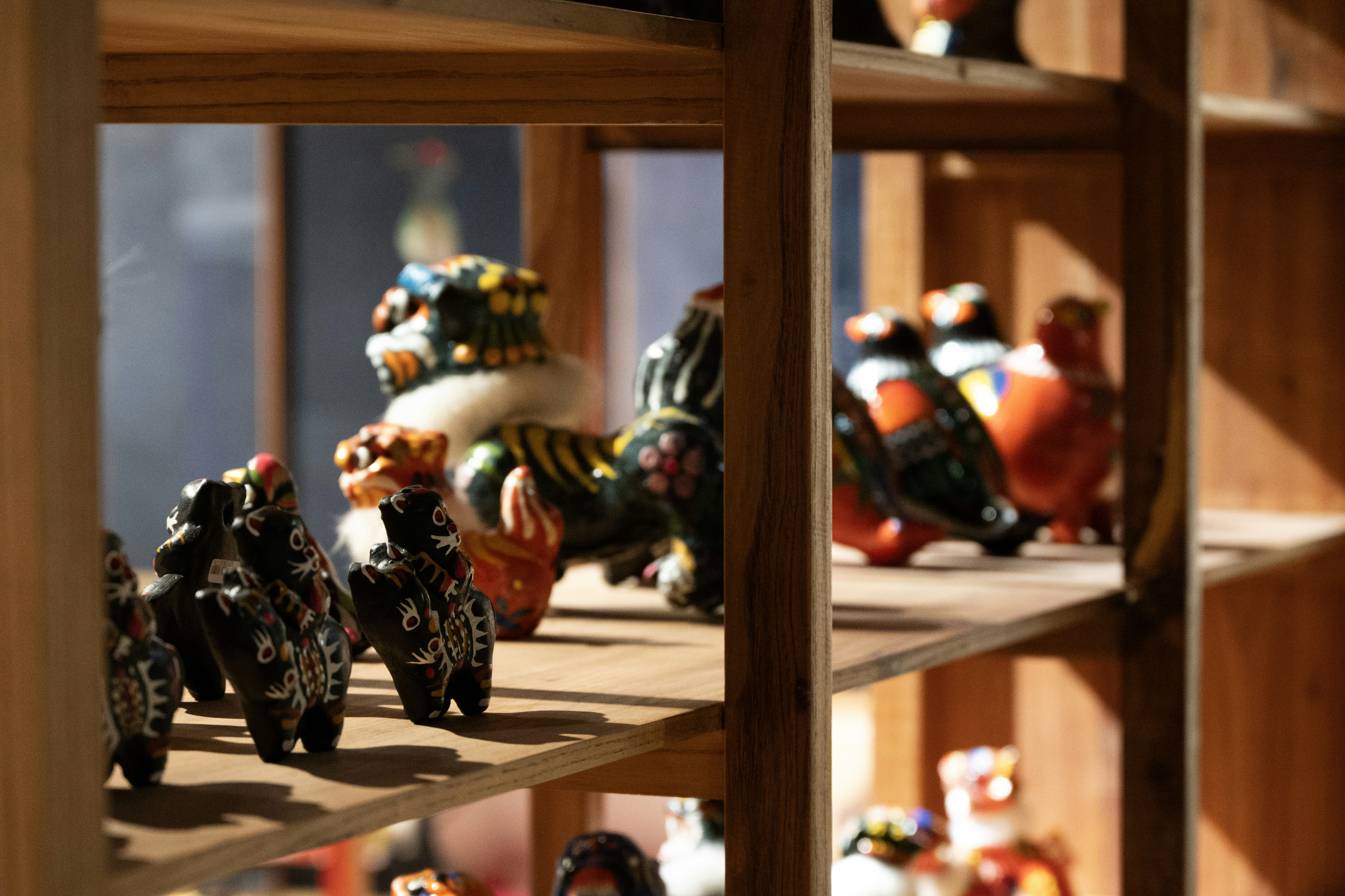 Tiny Painted Figures on a Wooden Shelf: A Colorful Walk Through a Handcrafted Display