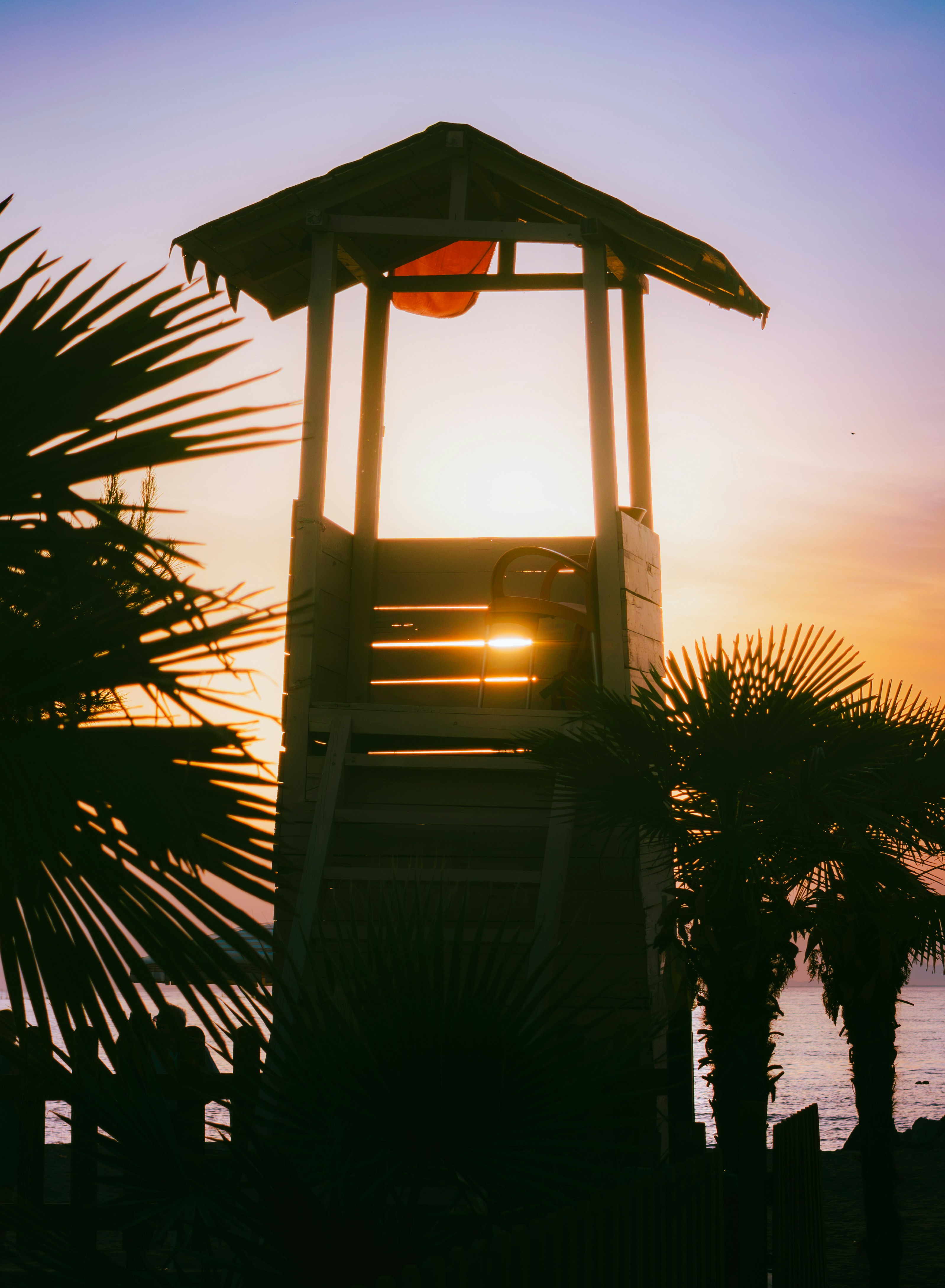 Sunlit Lifeguard Tower Framed by Silhouetted Palm Fronds at Dusk