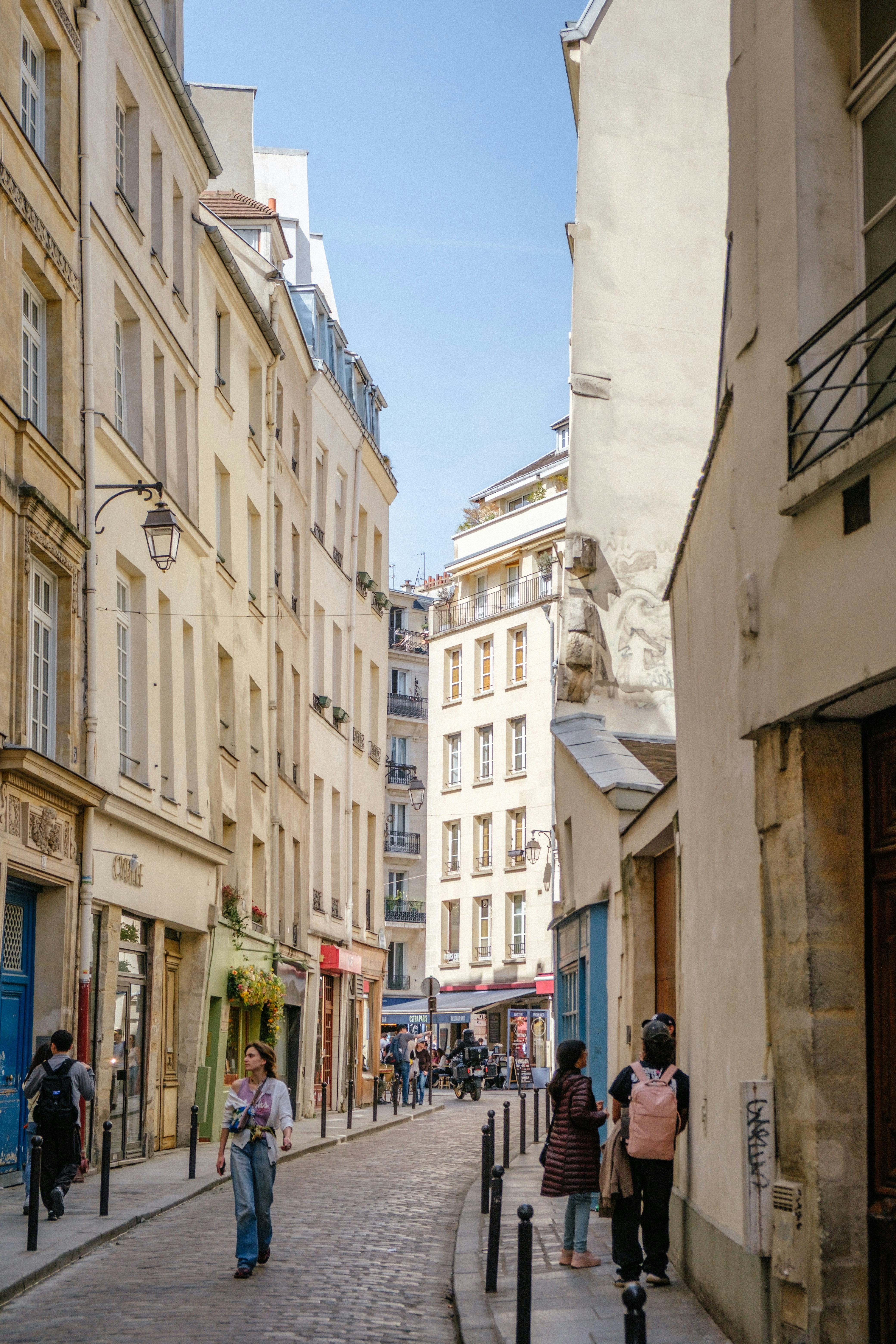 Sunlit Rue: People and Pastel Facades in a Quiet European Alley