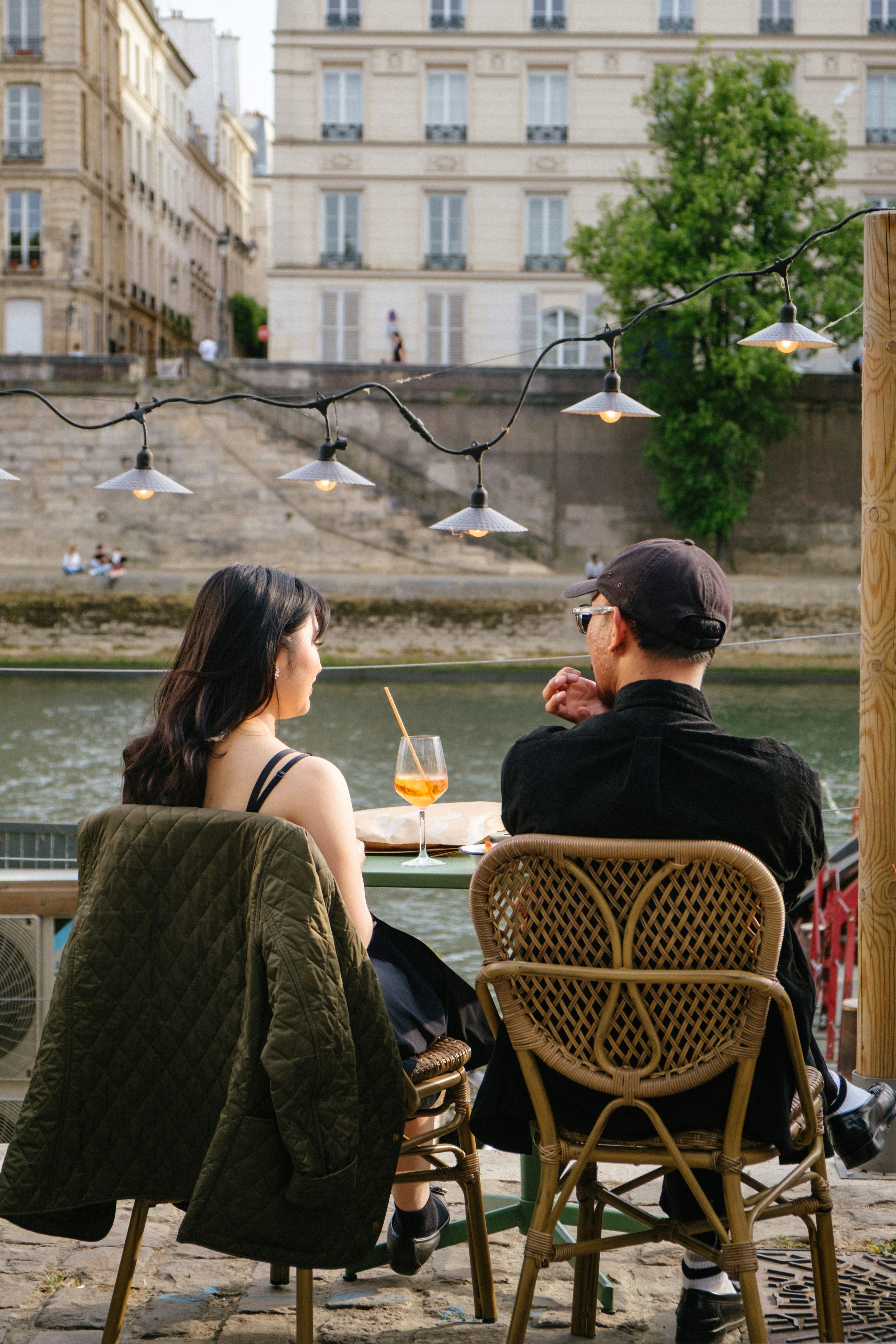 Afternoon by the Seine: Shared Conversation Under String Lights