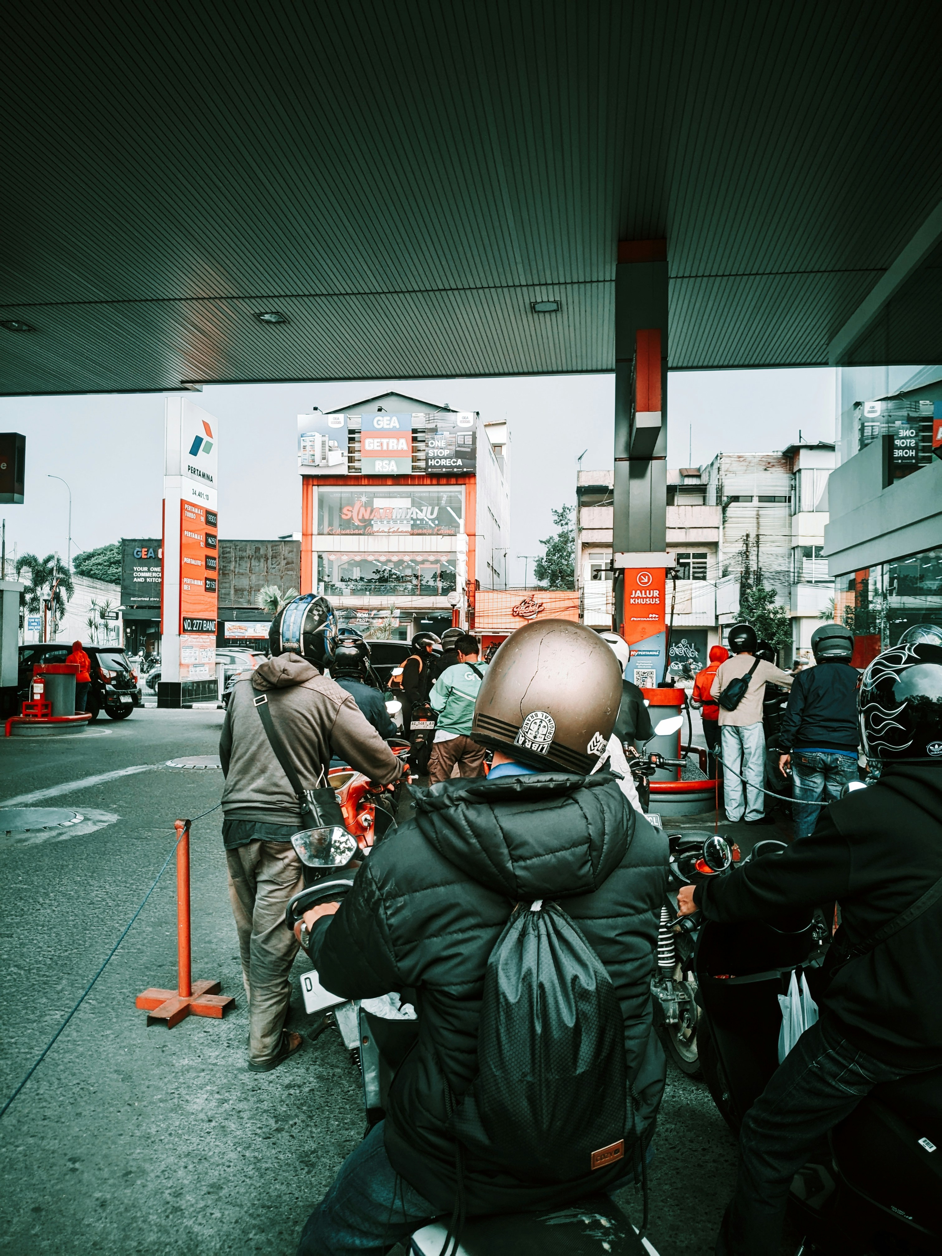 Motorcycle Queue Under a Canopy: Urban Busy at a Fuel Station