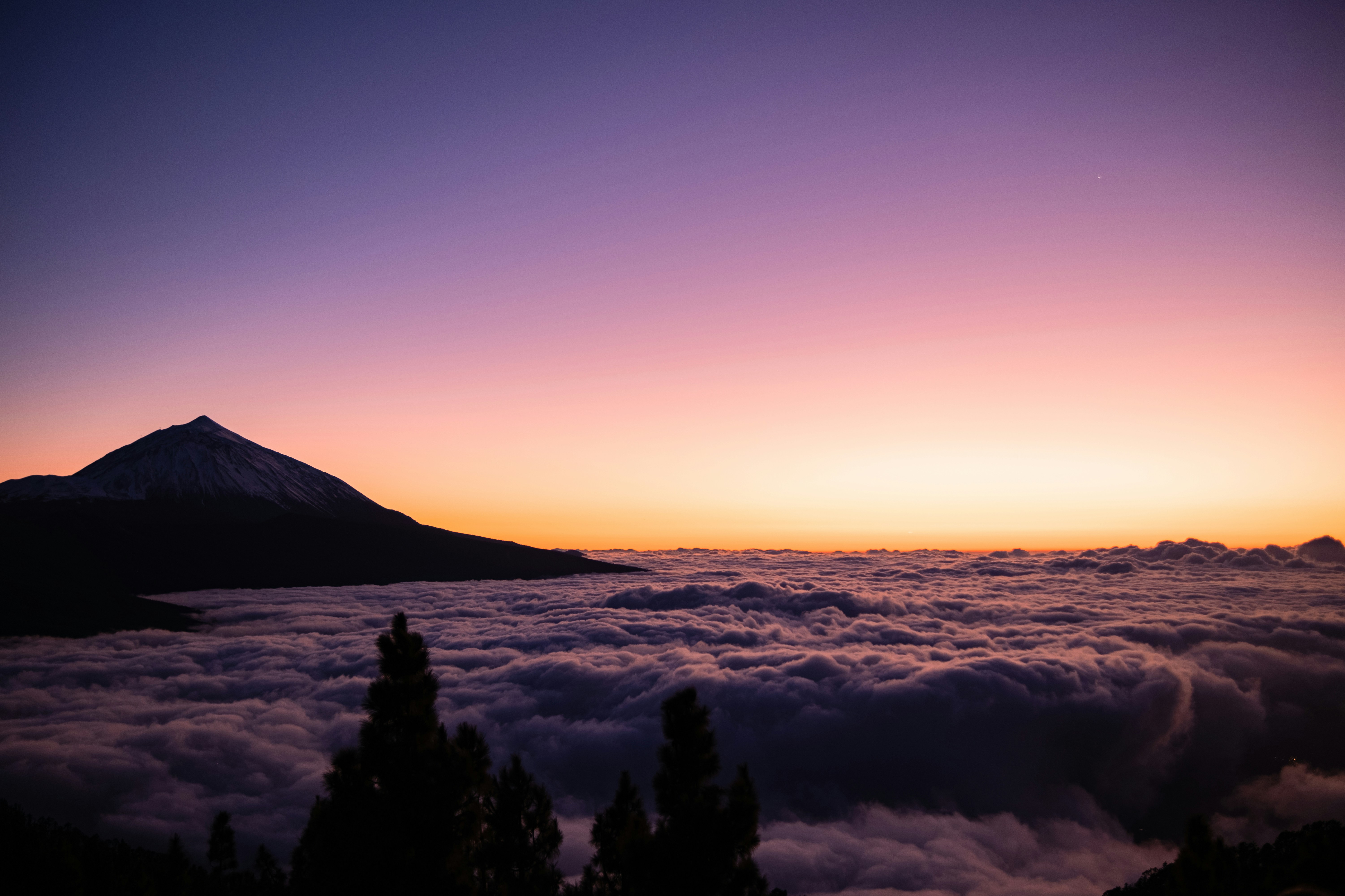 Above the Veil: A Snow-Capped Peak Above a Sea of Clouds at Sunset