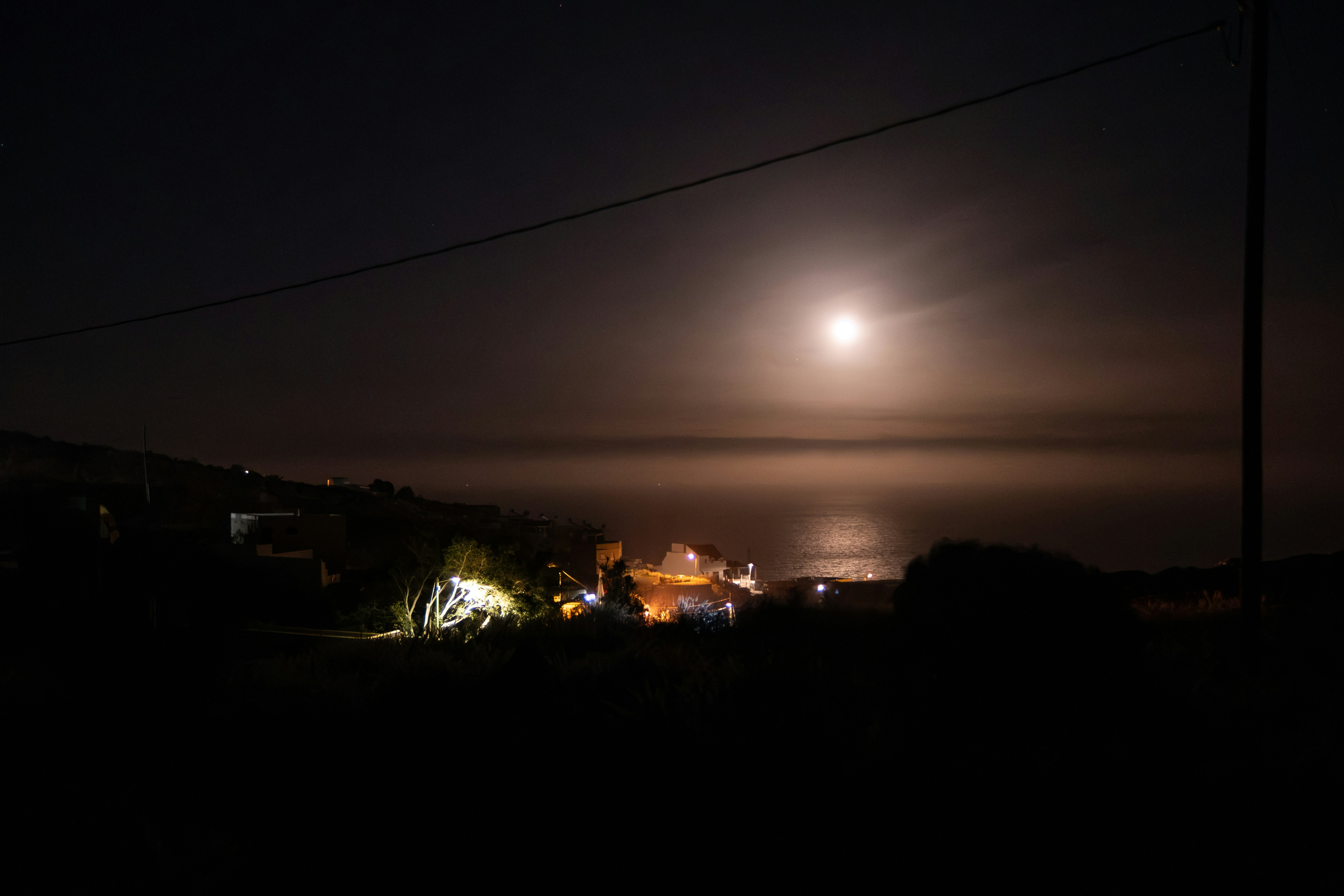 Moonlit Coastline: Quiet Village Under a Halo