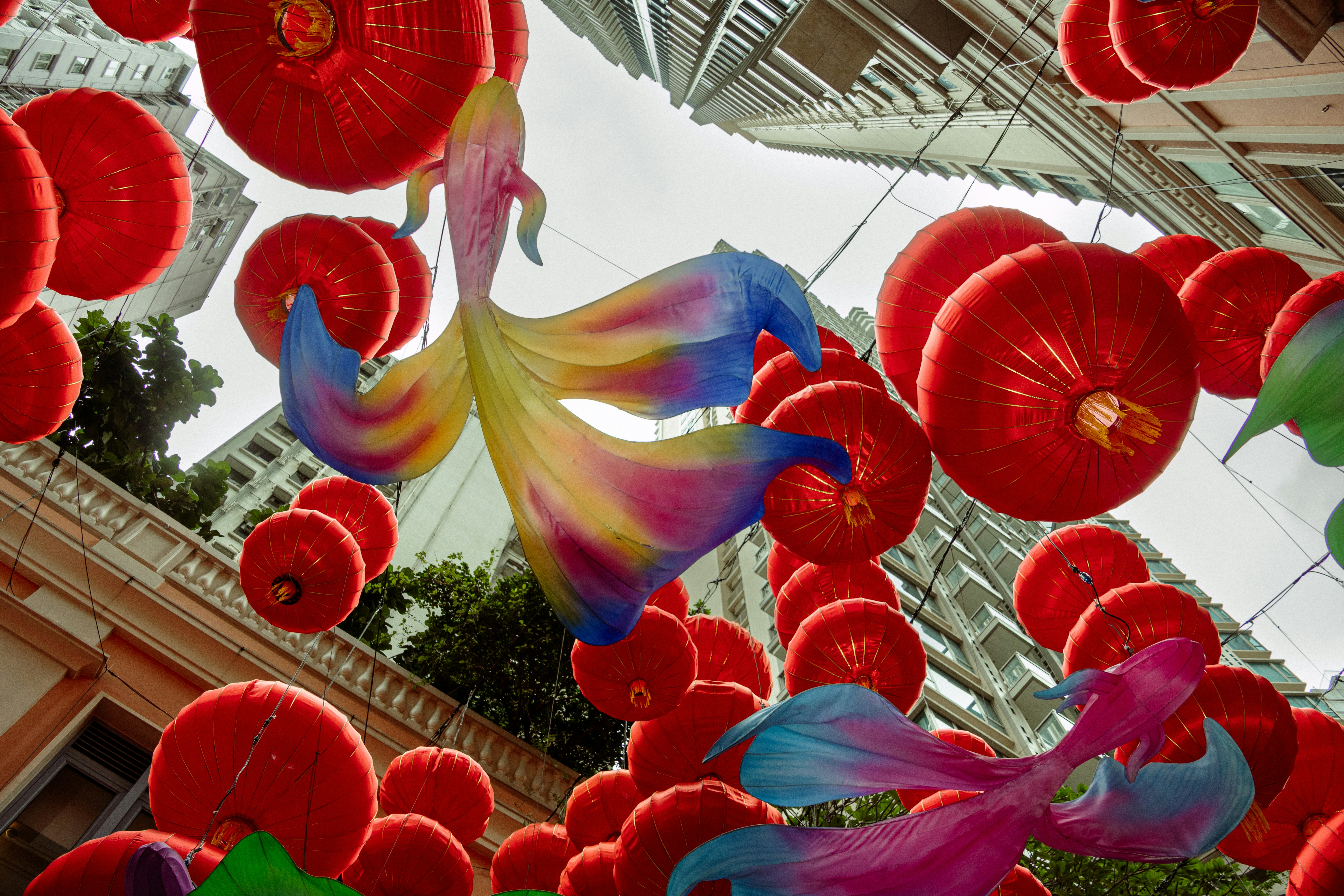 Floating Fiesta: Colorful Lanterns Against Urban Sky
