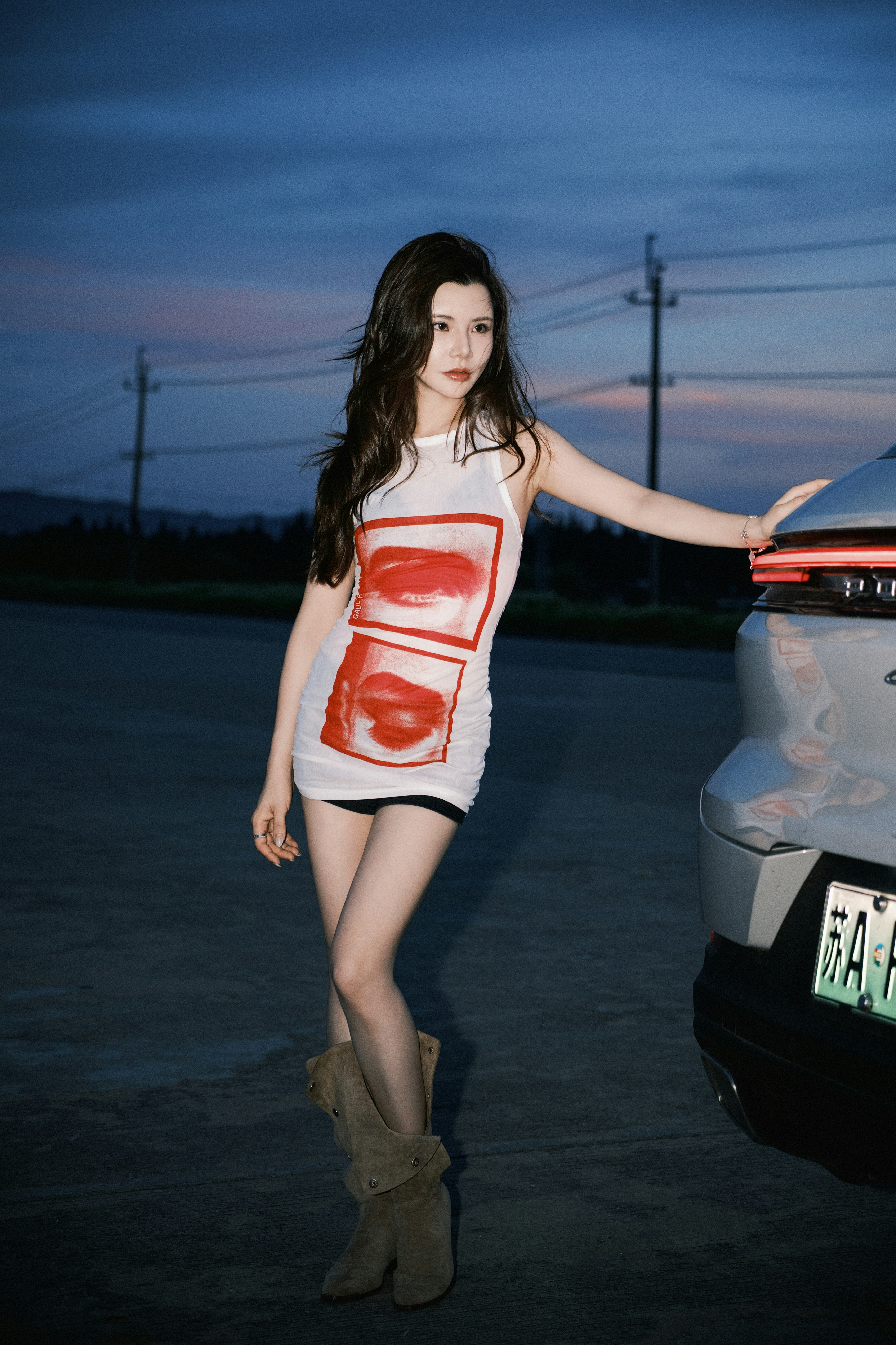 Neon-lit pulses: a dancer in a painted white dress by the car
