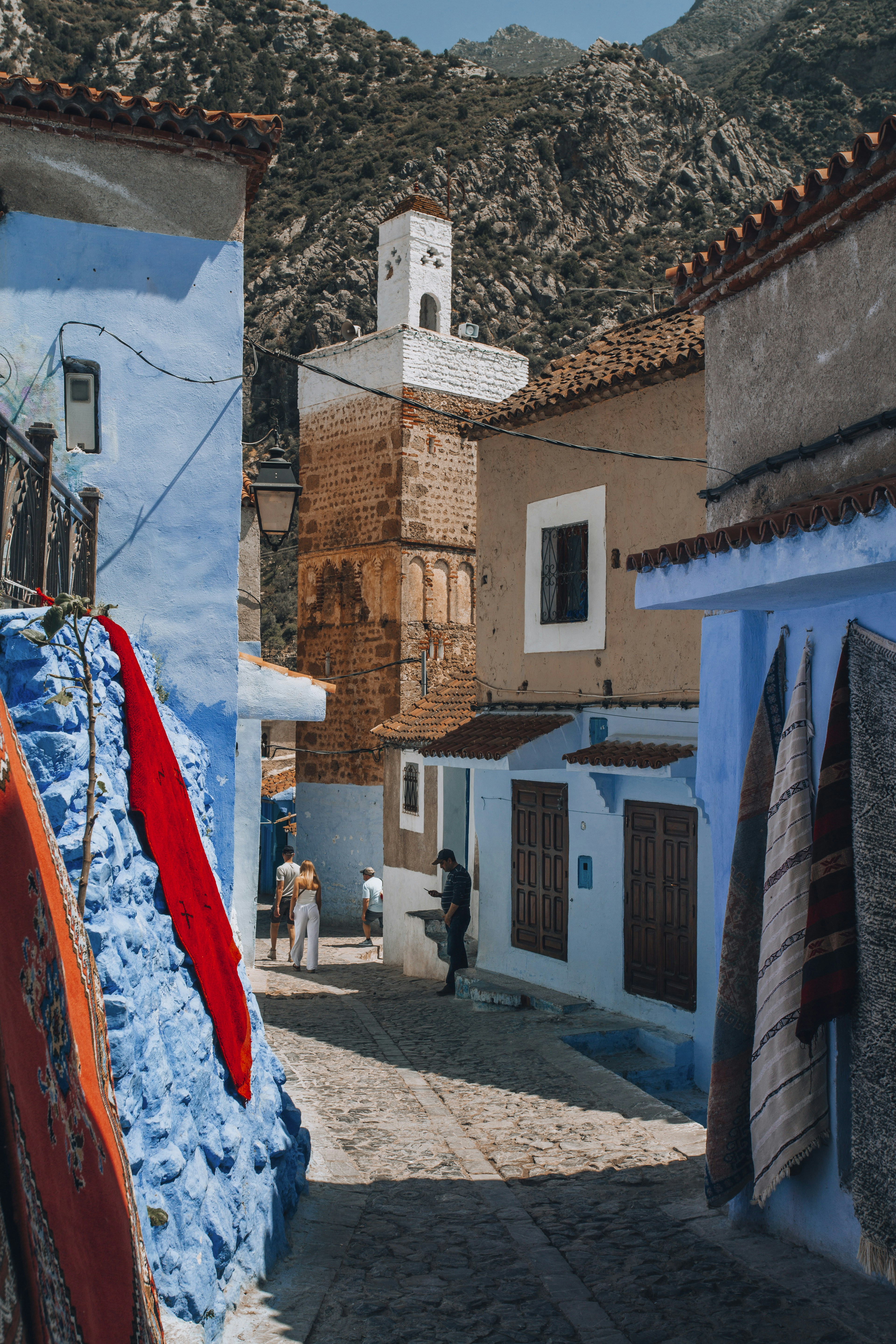 Blue-washed alleys of a sunlit Moroccan village with a distant church tower