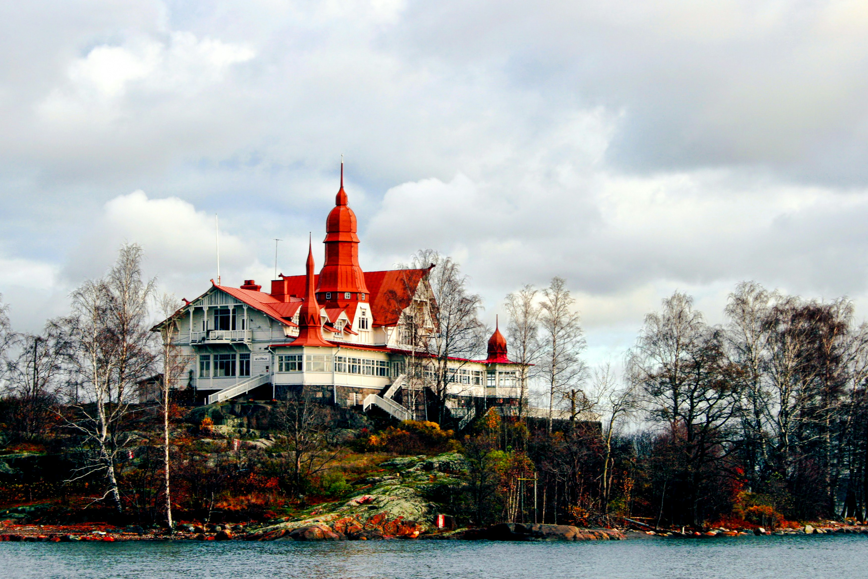 Red-roofed villa on a rocky promontory overlooking a calm inlet