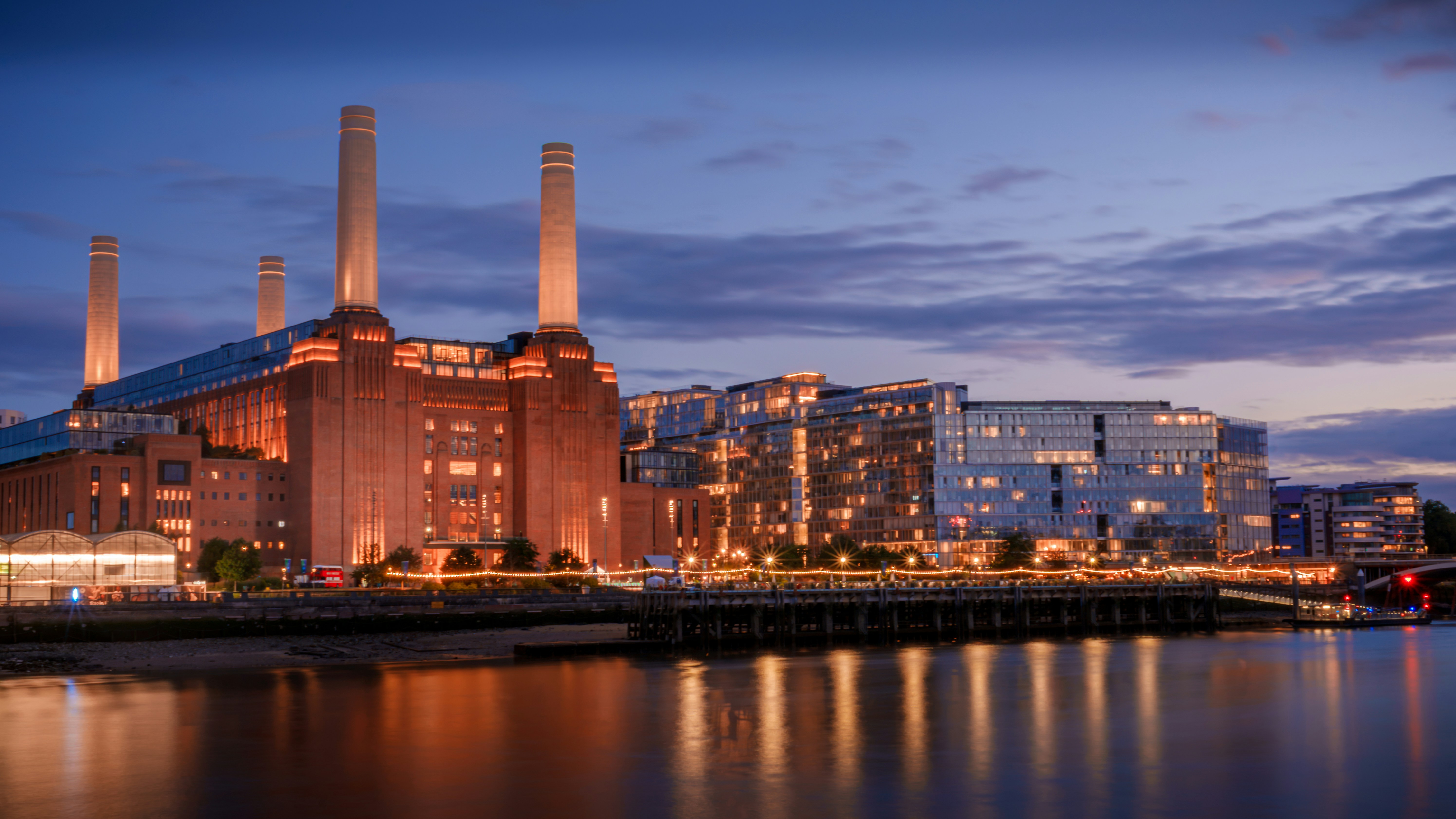 Industrial glow along the river: factory chimneys and city lights at blue hour