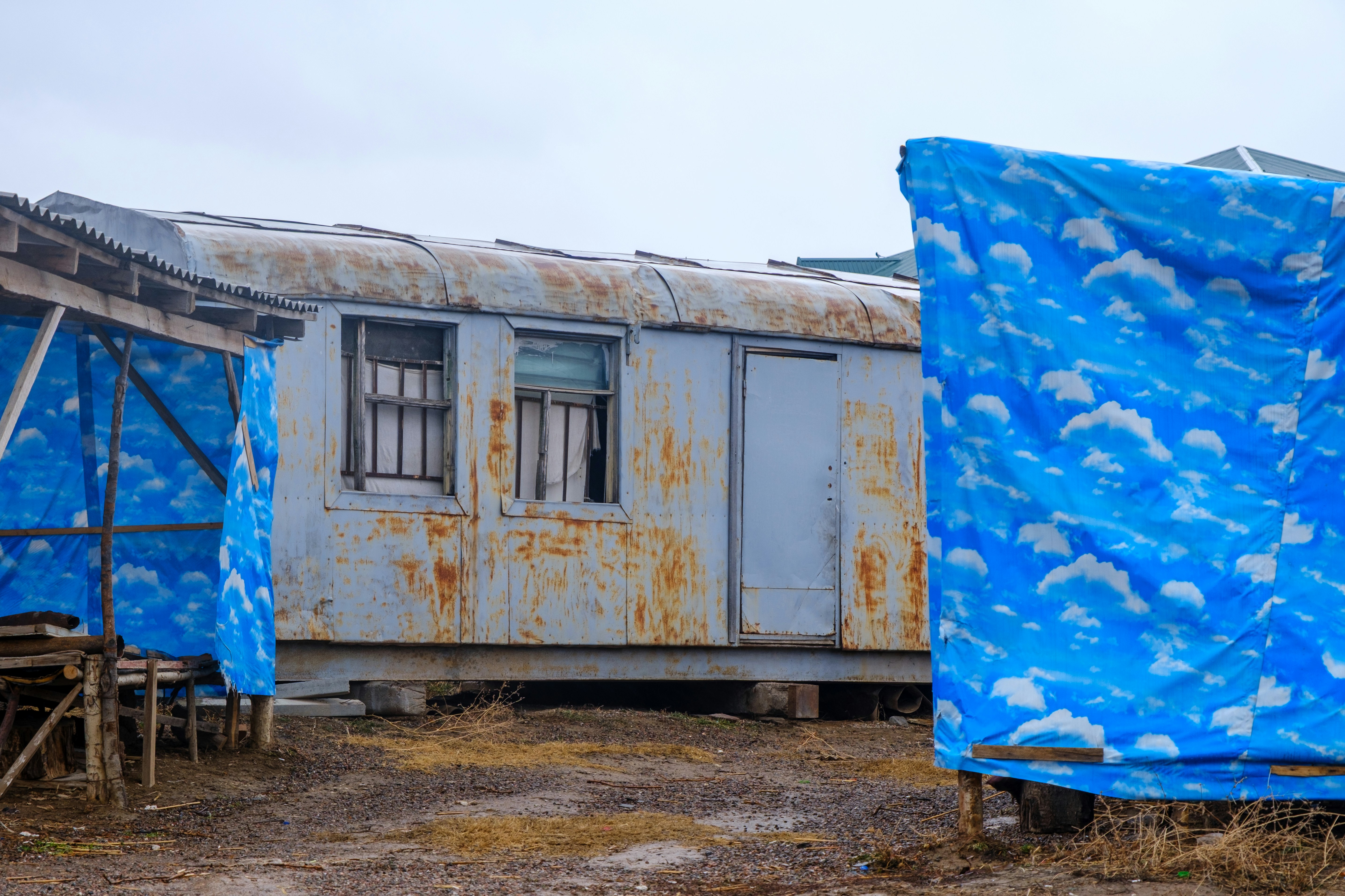 Rust and Blue Shelter: Abandoned Dwelling in Blue-Tarp Light