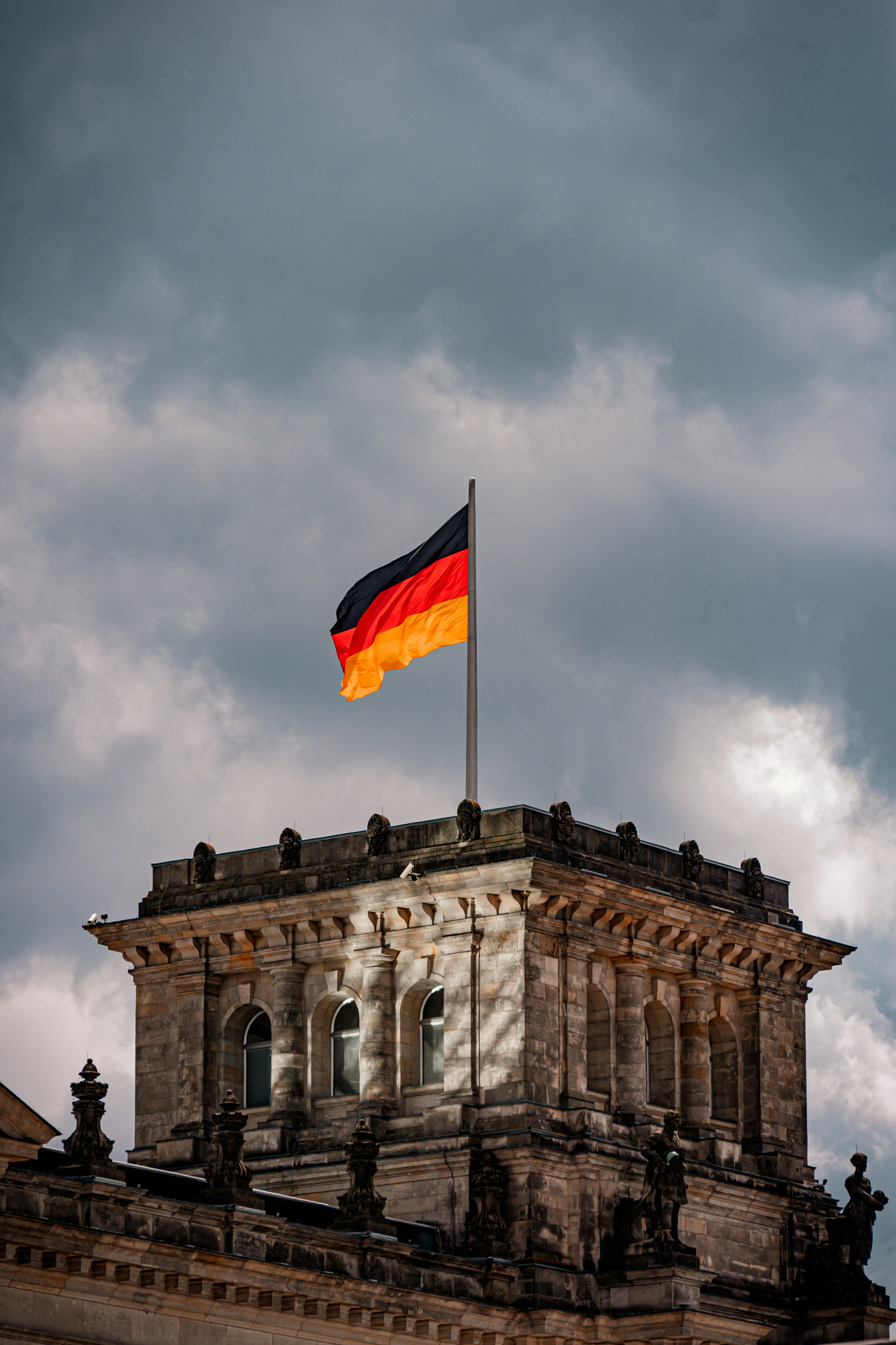 Flag atop a historic façade under dramatic skies