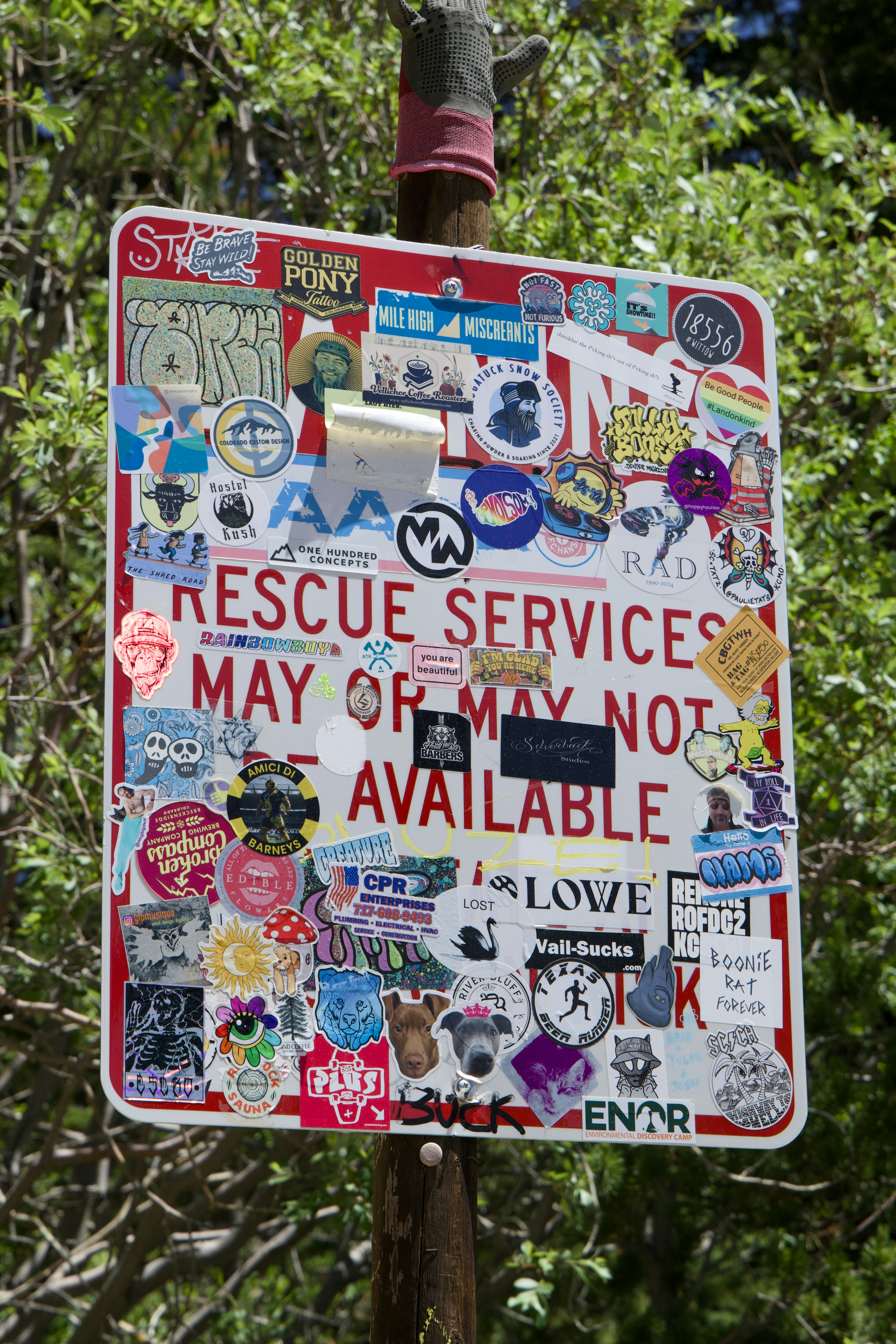 Sticker Mosaic on Public Sign: A Collage of Messages and Color
