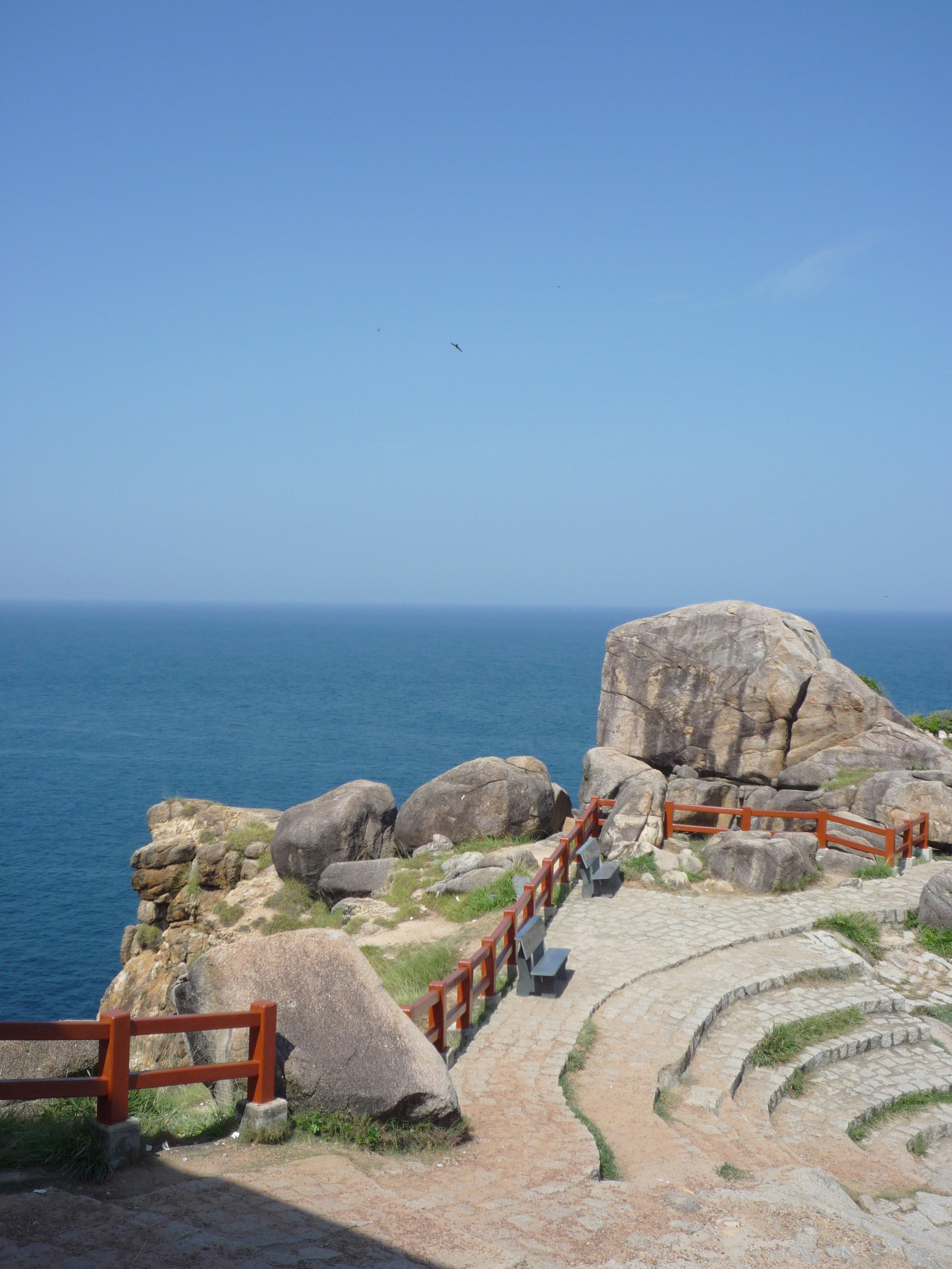 Clifftop Path by the Sea: Weathered Rocks, Red Railings, and A Quiet Horizon