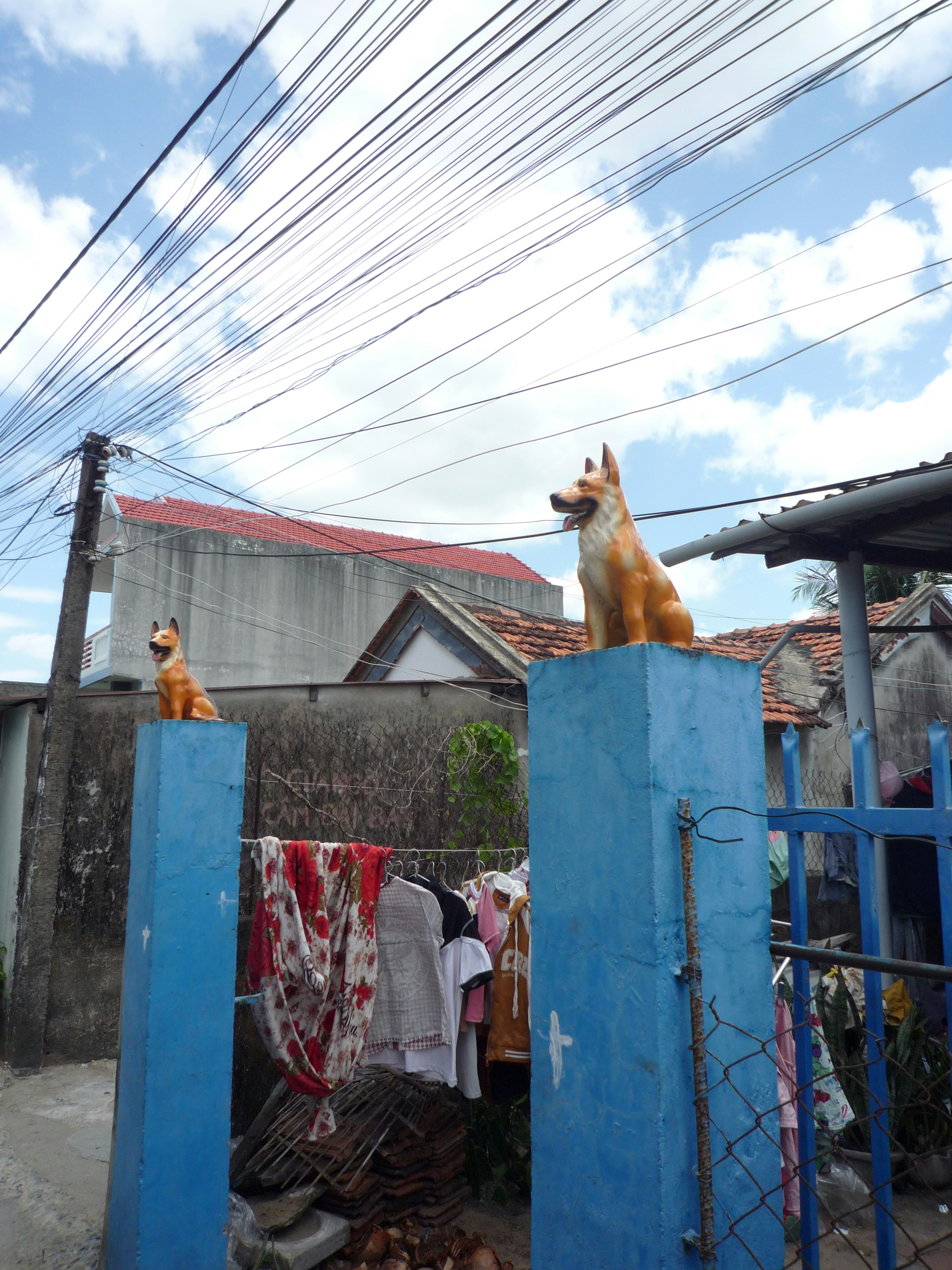 Two Blue Pillars Guarding Summer Sky: Dog Statues Above the Gate