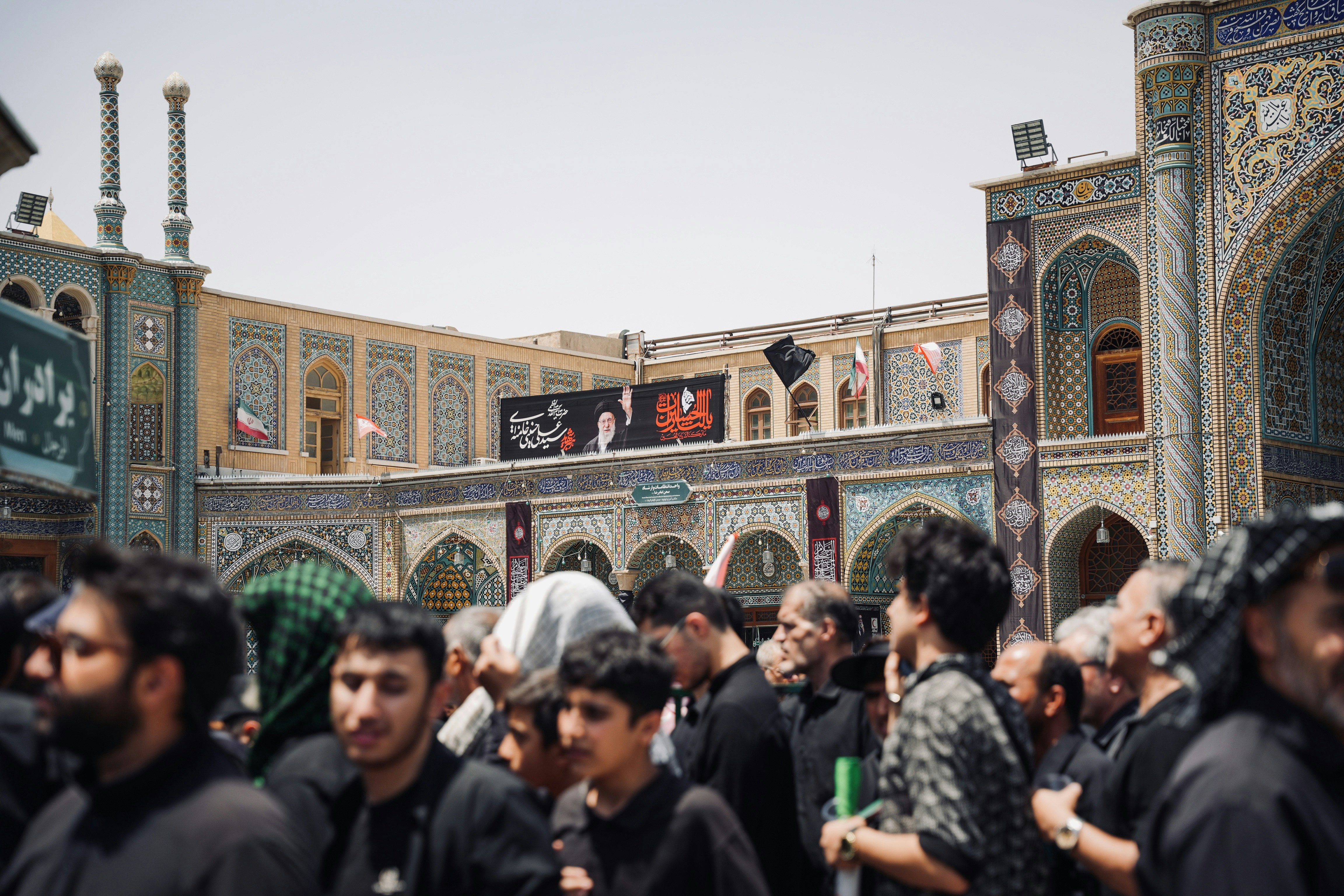 Crowd at a Persian courtyard festival framed by ornate tilework