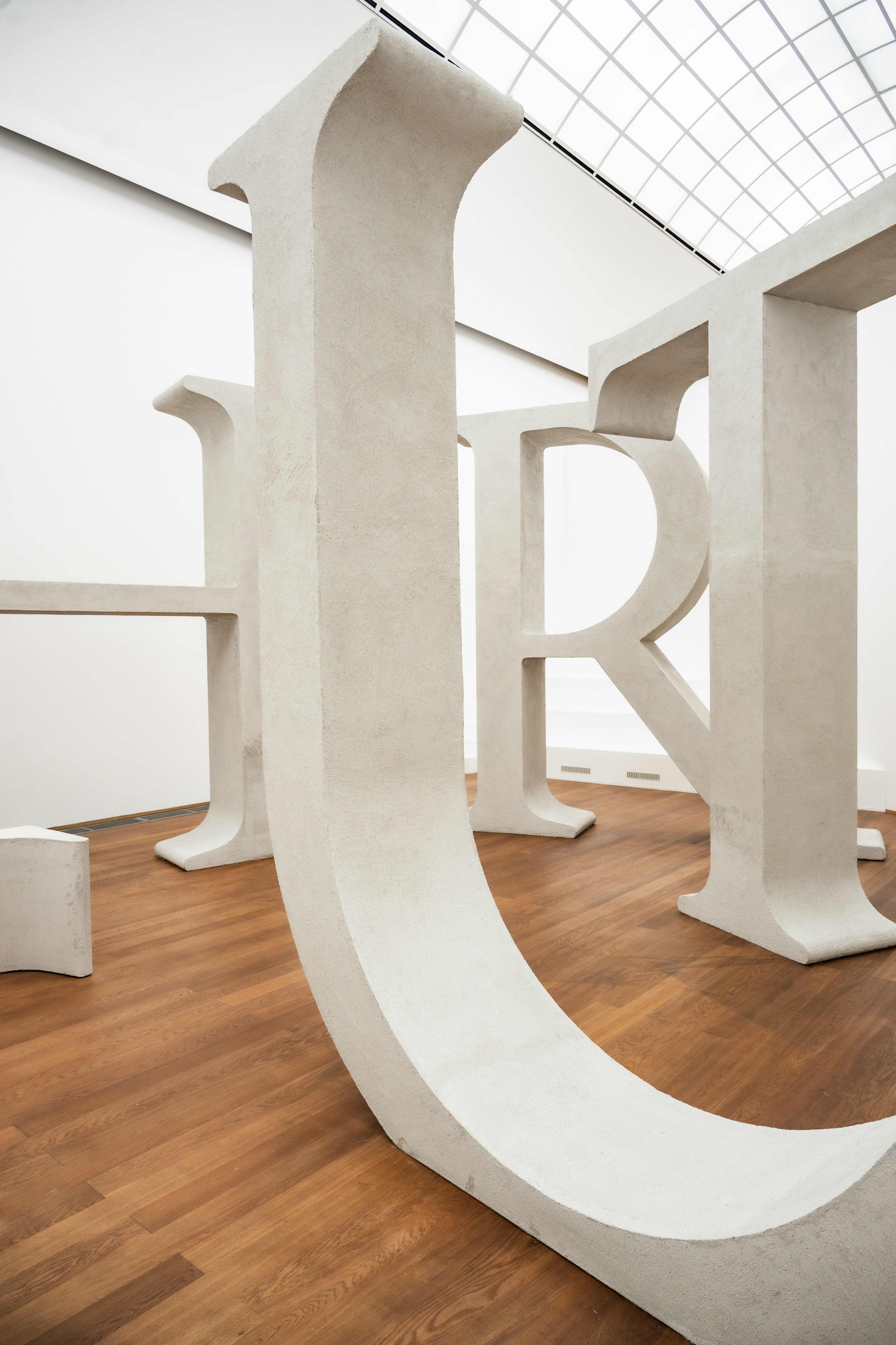 Monumental Letters: A Gallery of Curved White Forms on Warm Wood
