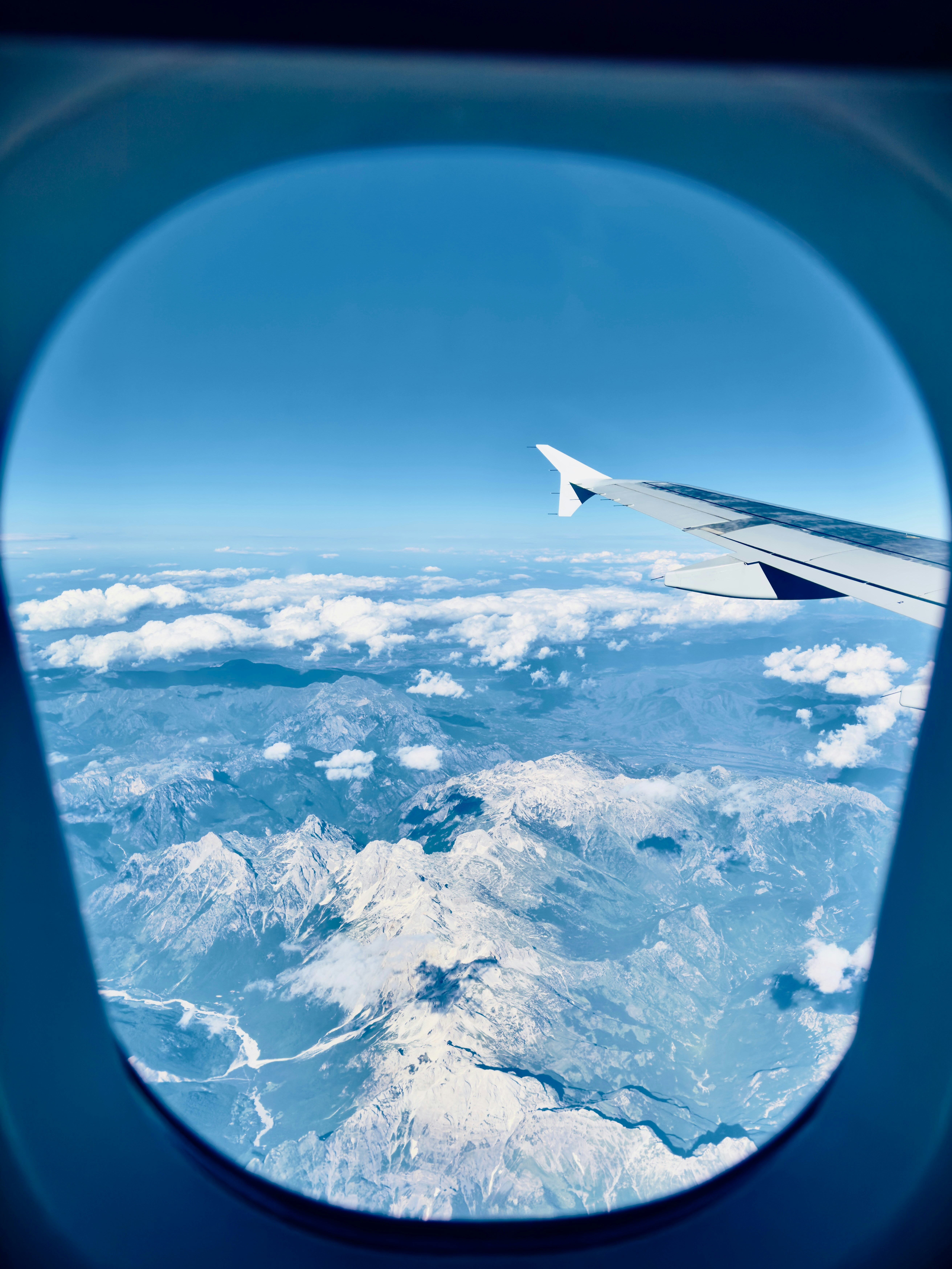 Wingtip View: A Snow-Capped Horizon Through an Airplane Window