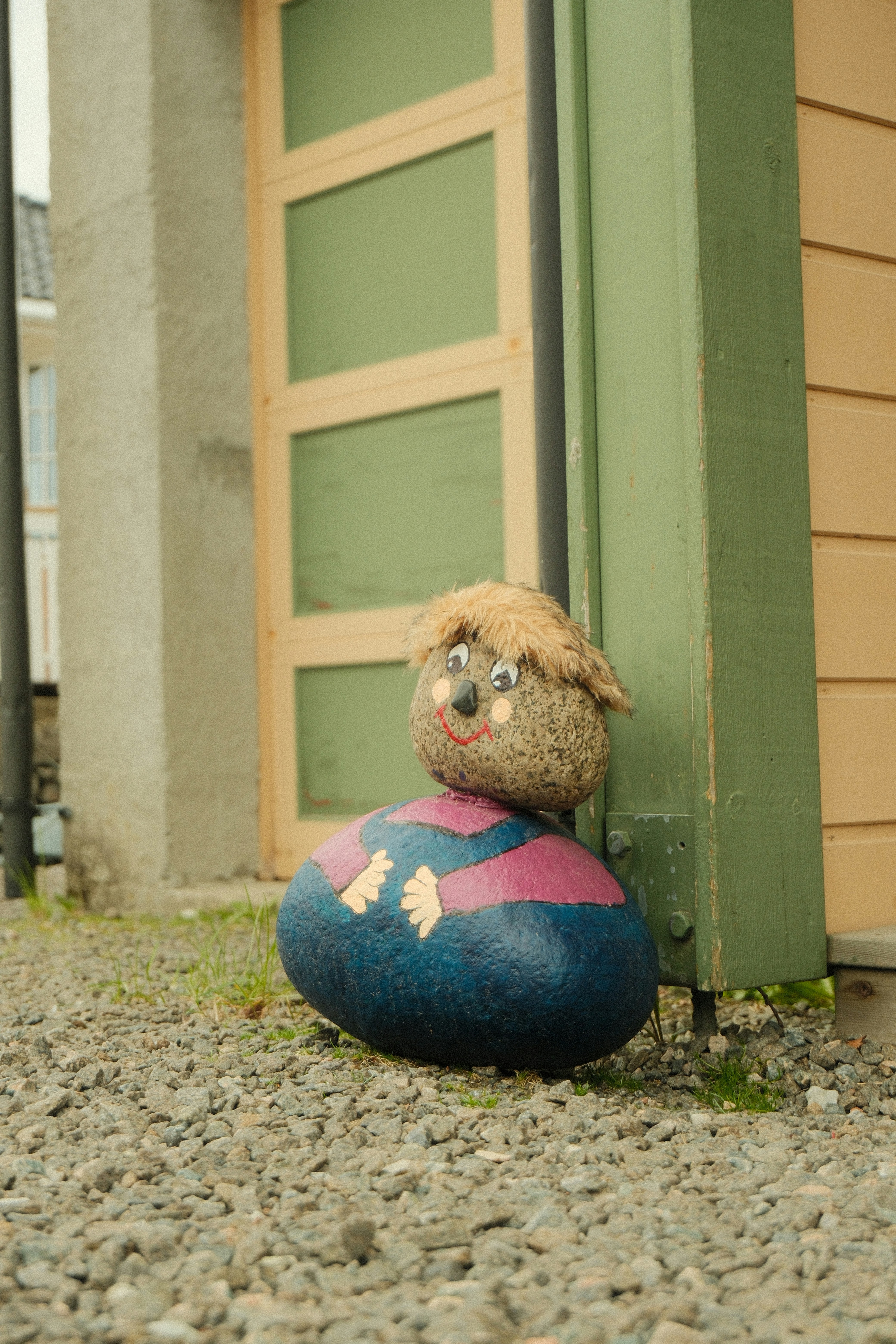 Whimsical Cement Figure Resting by a Green Doorway