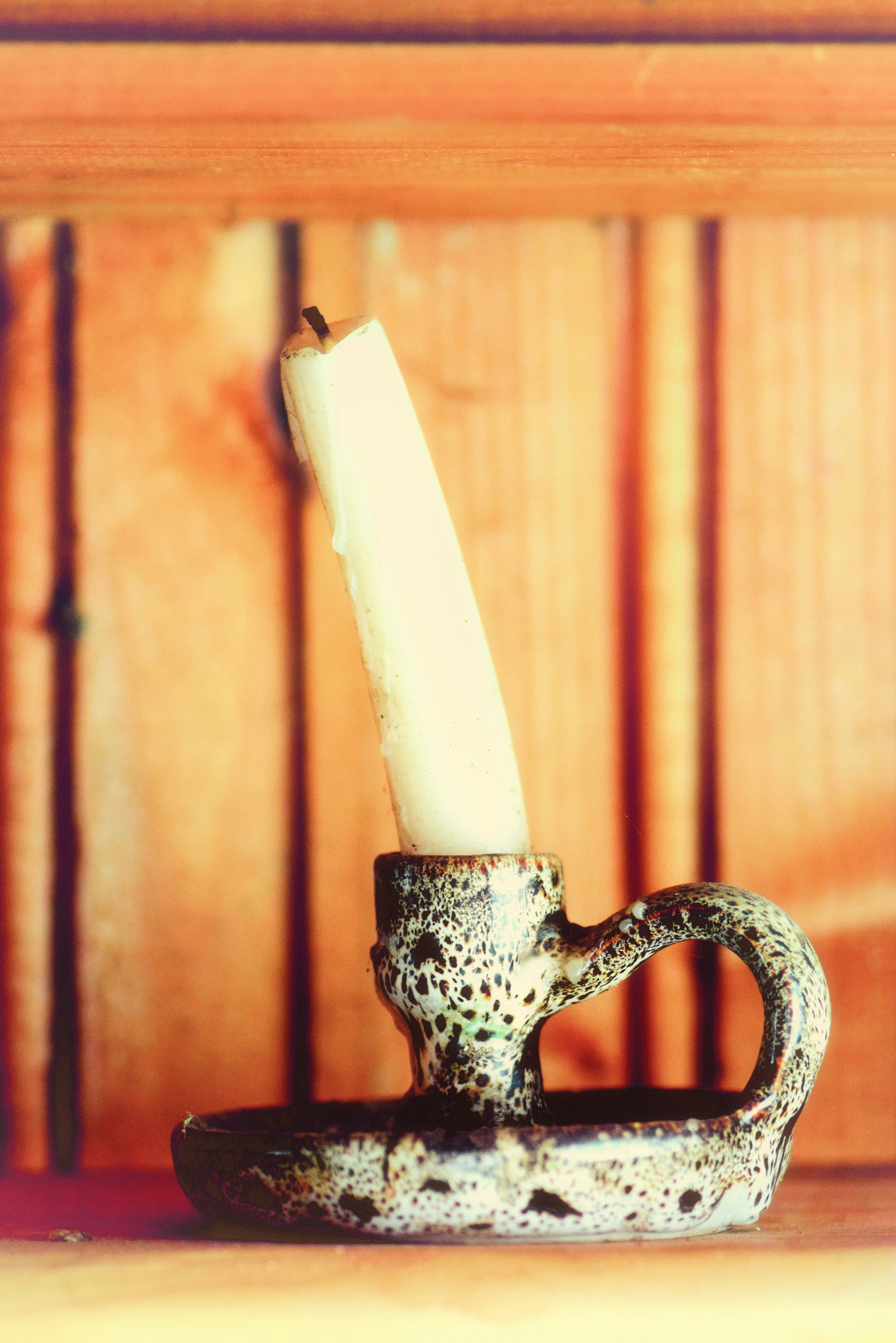 Frayed Candle in a Speckled Holder—Warm Wood Backdrop