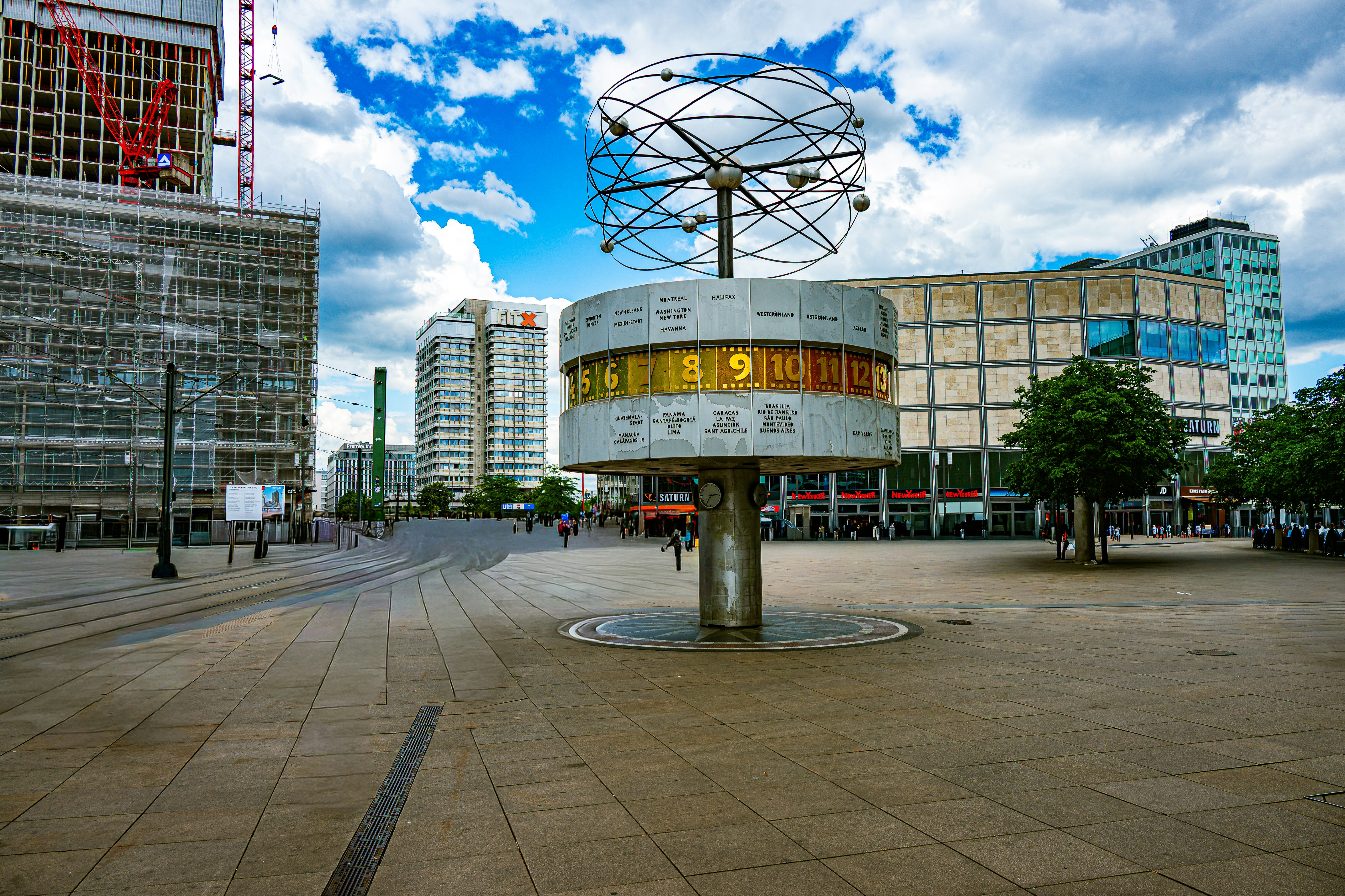 Circular world clock in a modern plaza under a blue sky
