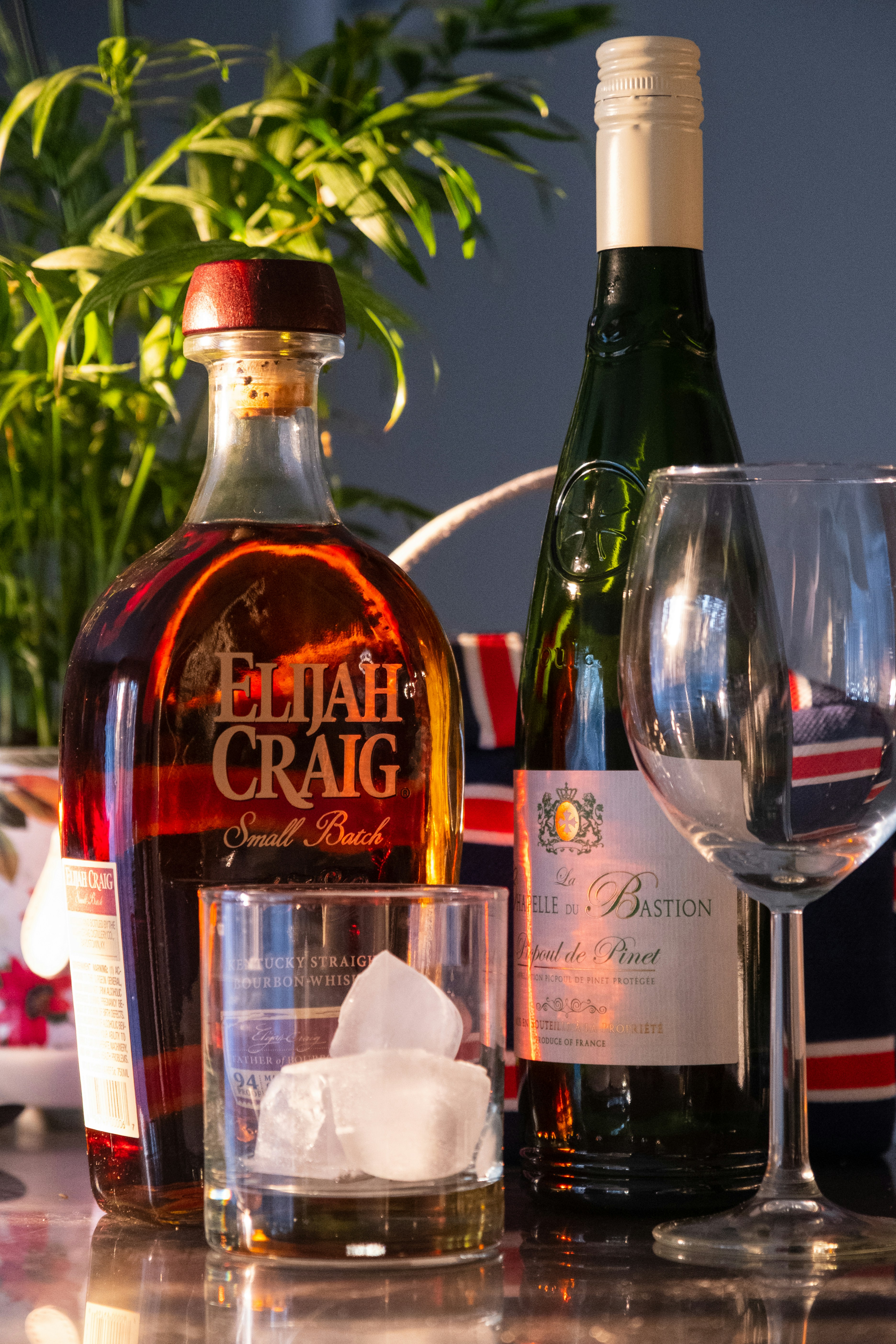 Whiskey and White Wine Toast: Bottles, Glasses, and Ice on a Dim Table
