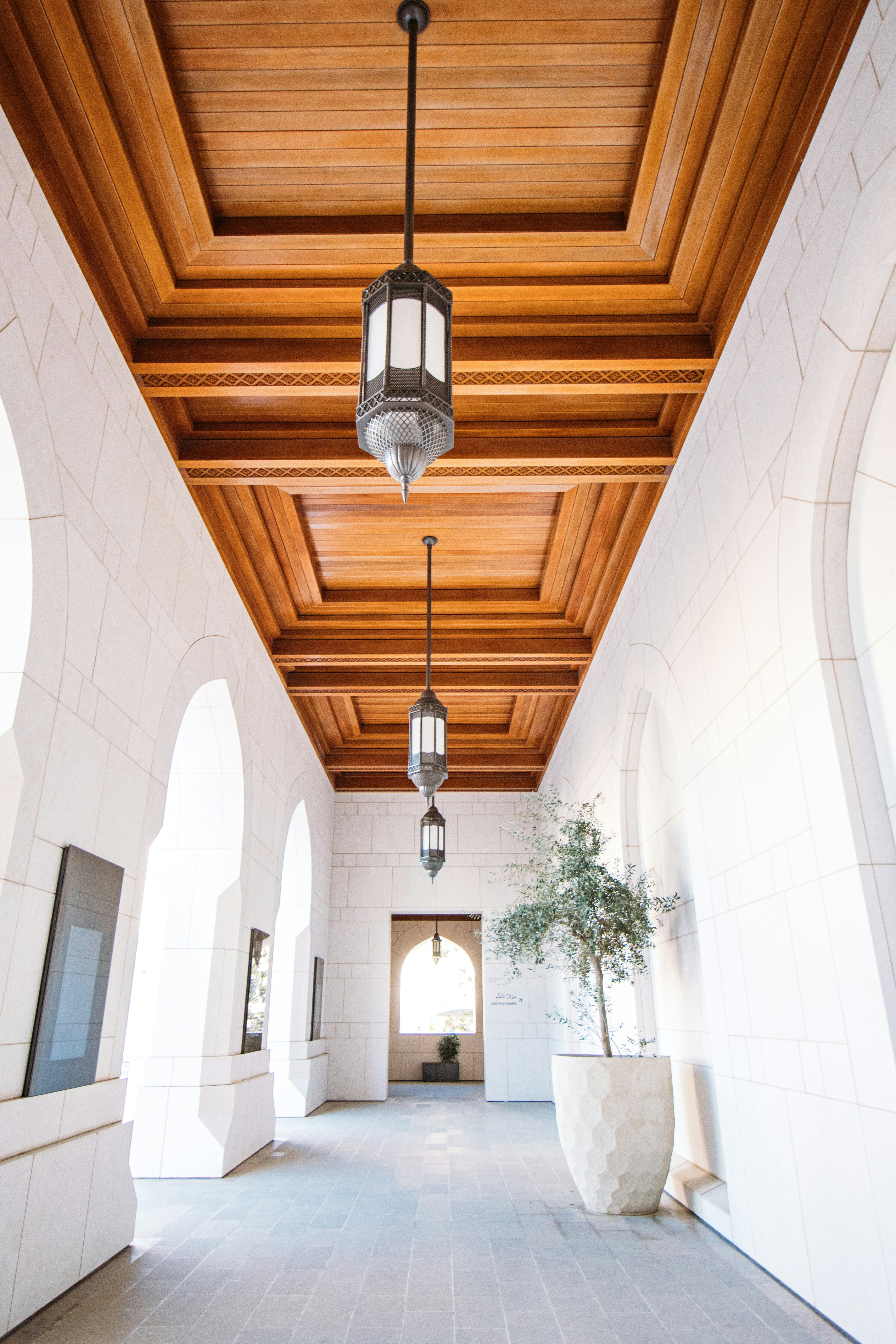 Symmetrical Lanterns Line a Marble Corridor Under Warm Wood Ceilings