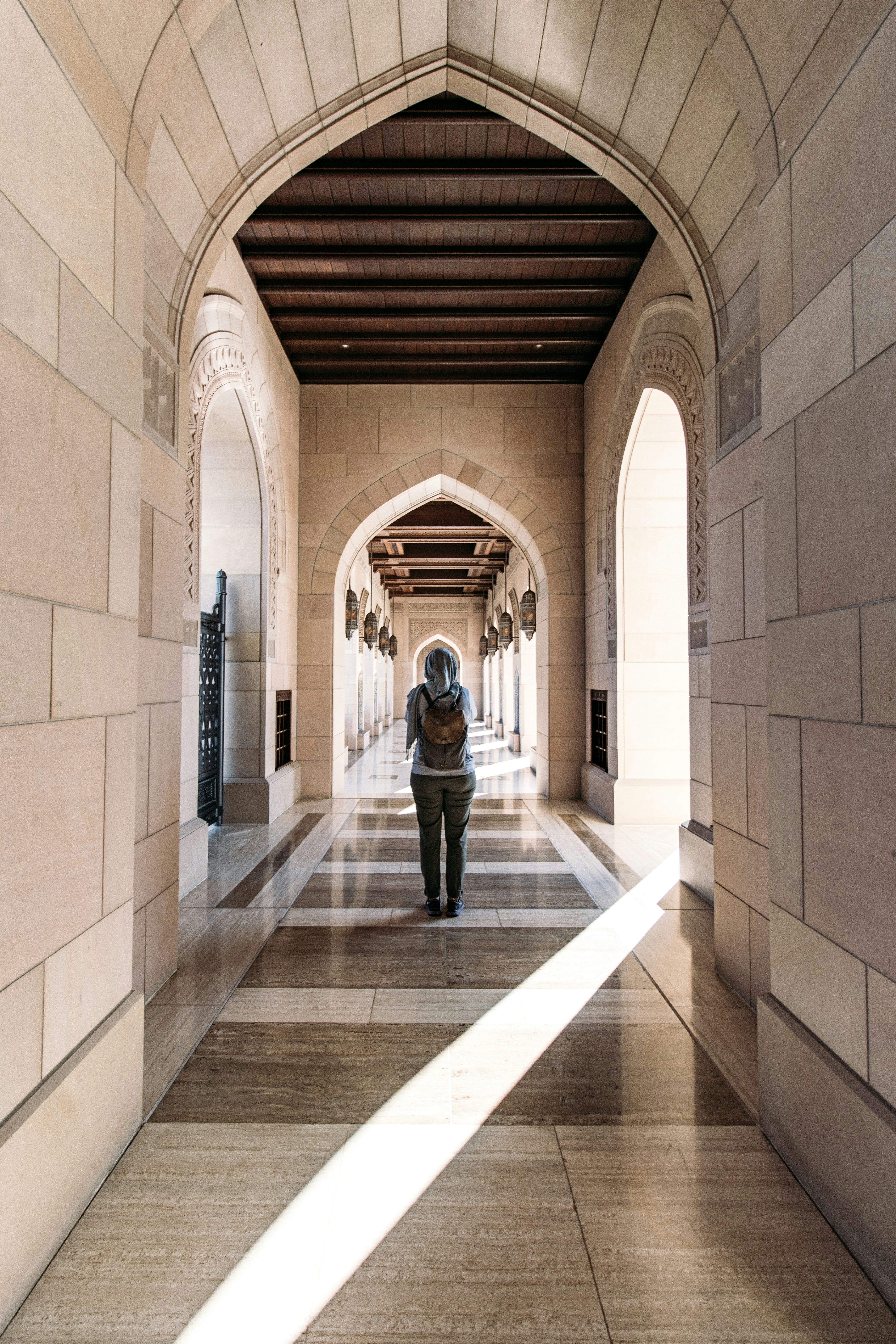 Traveler in a Marble Arcade: Light Stripes Through Archway