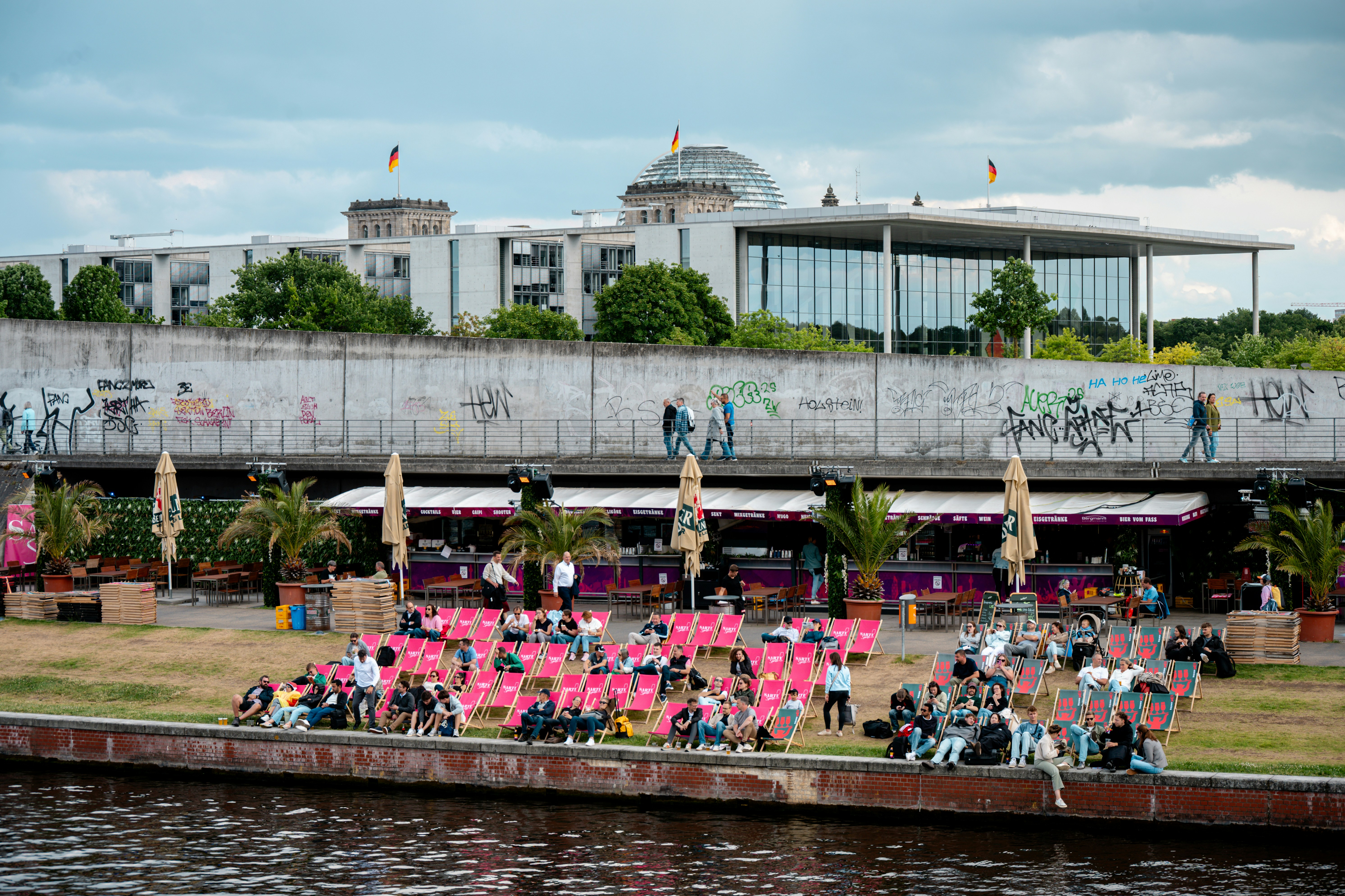 Lawnchairs by the River: People enjoy a sunny day at a riverside pavilion