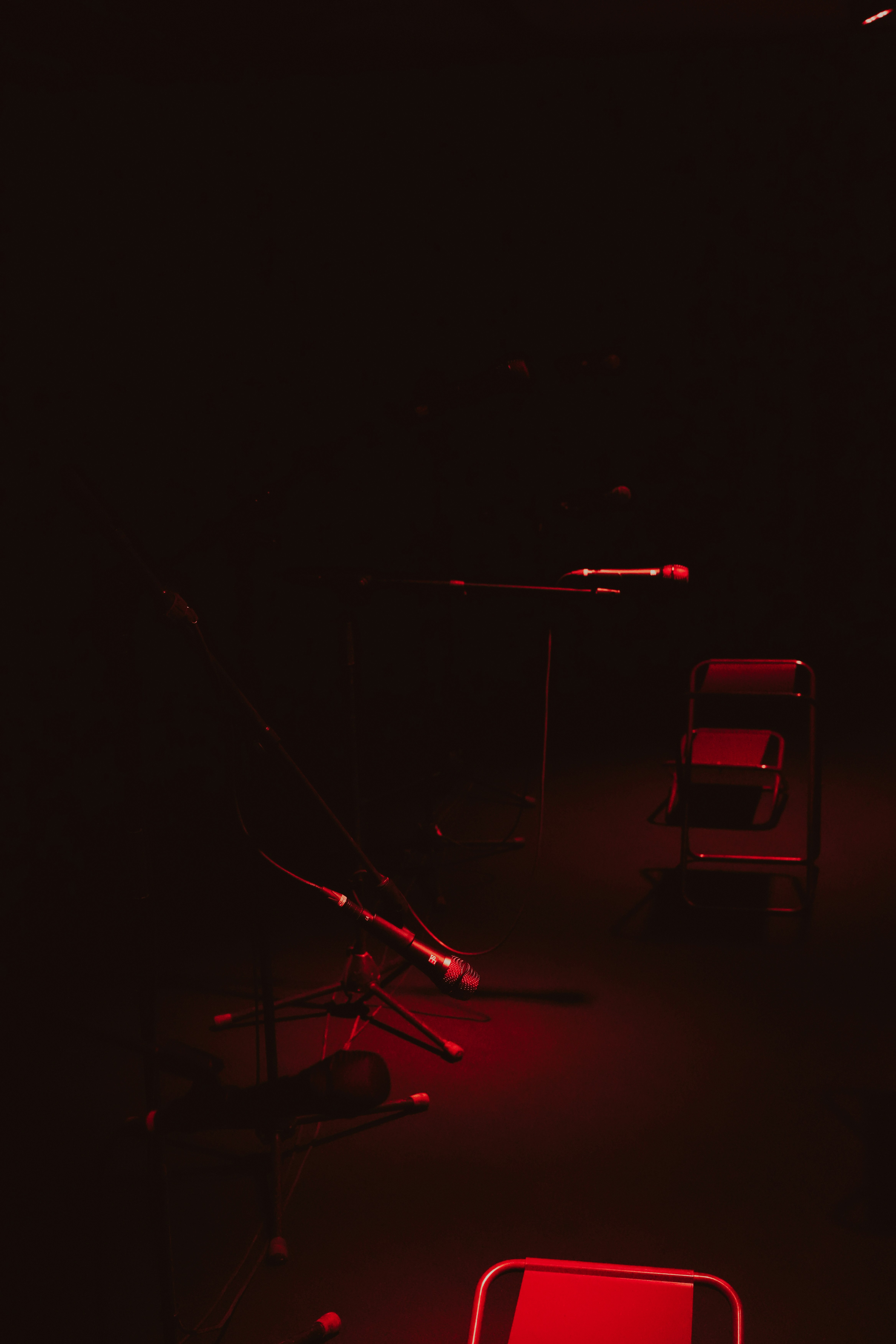 Red Spotlight Silence: A Quiet Stage with Microphone and Chairs