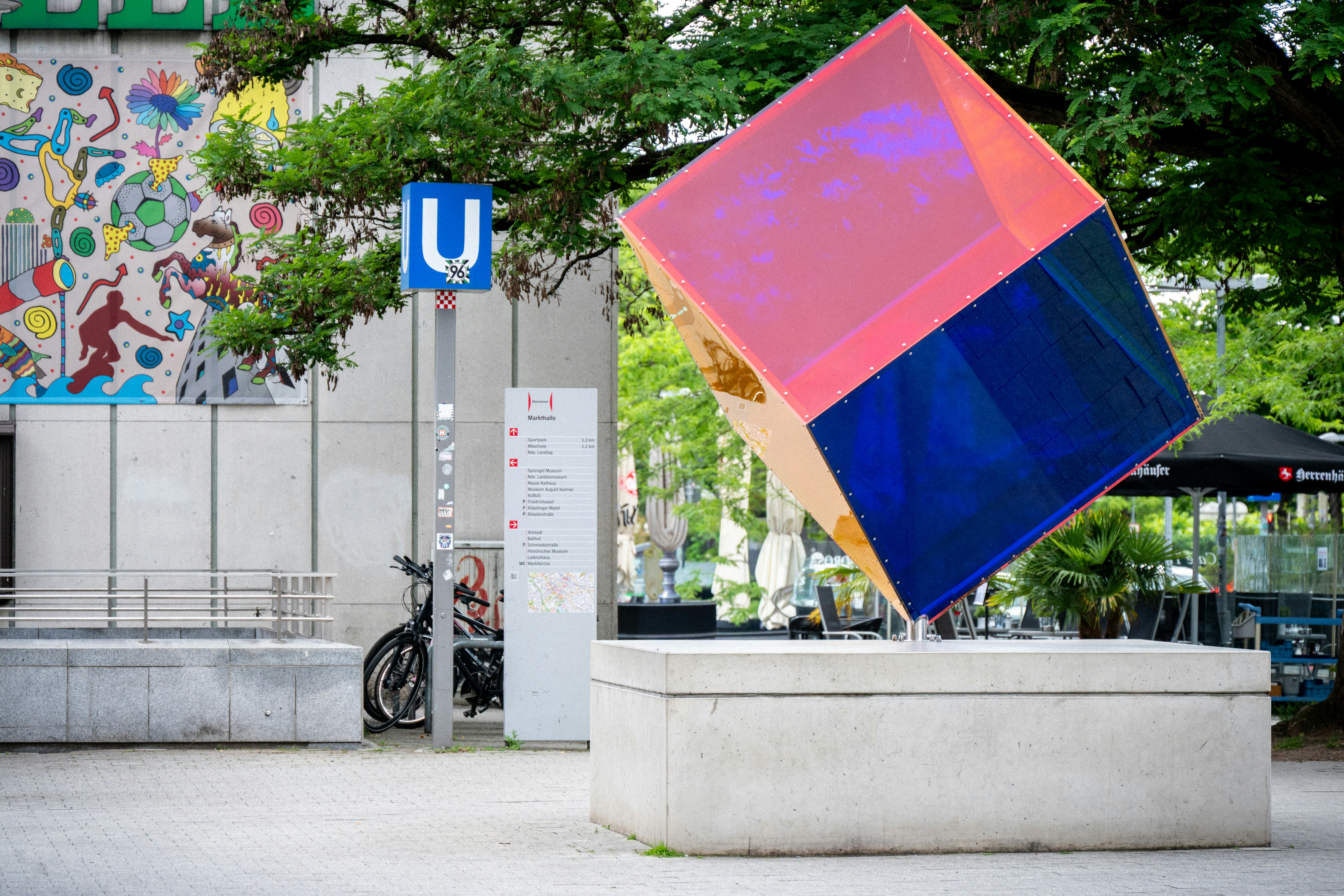 Urban sculpture and transit mural: a vibrant cube perched over a plaza