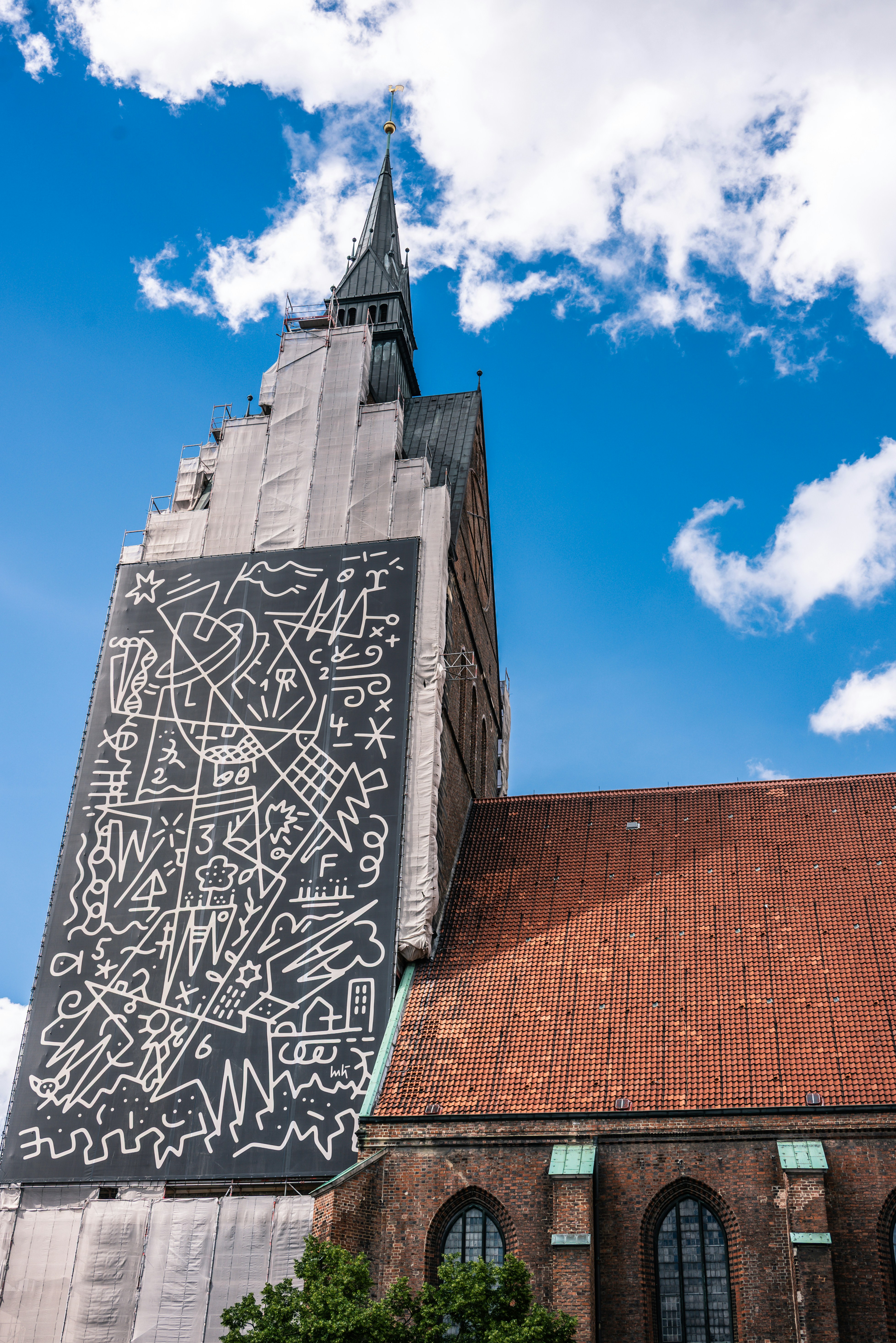 Abstracted Facade: A Cathedral Torre Adorned with White Glyphs Against a Brisk Sky