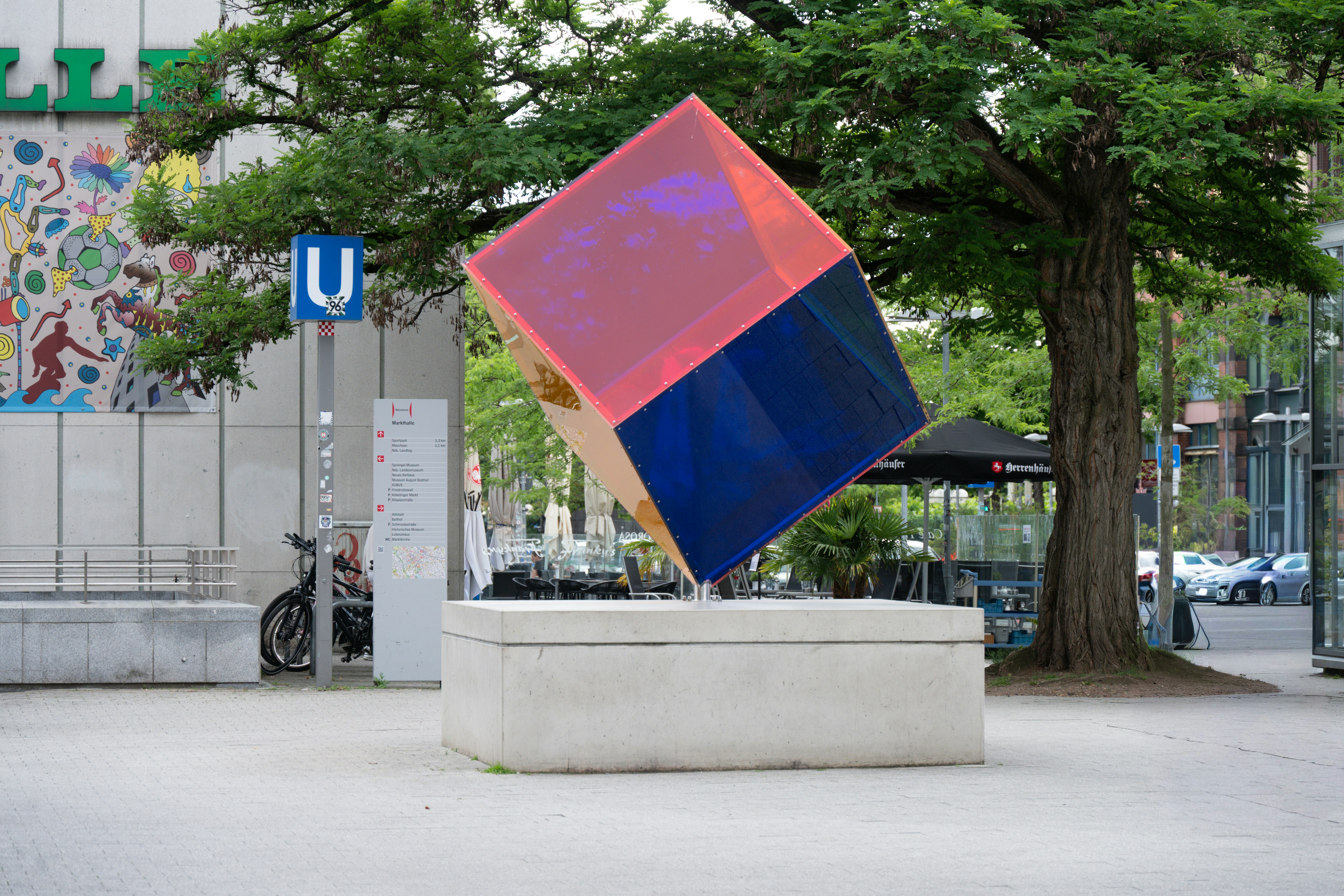 Colored Cubes Balance on a Concrete Pedestal in an Urban Square