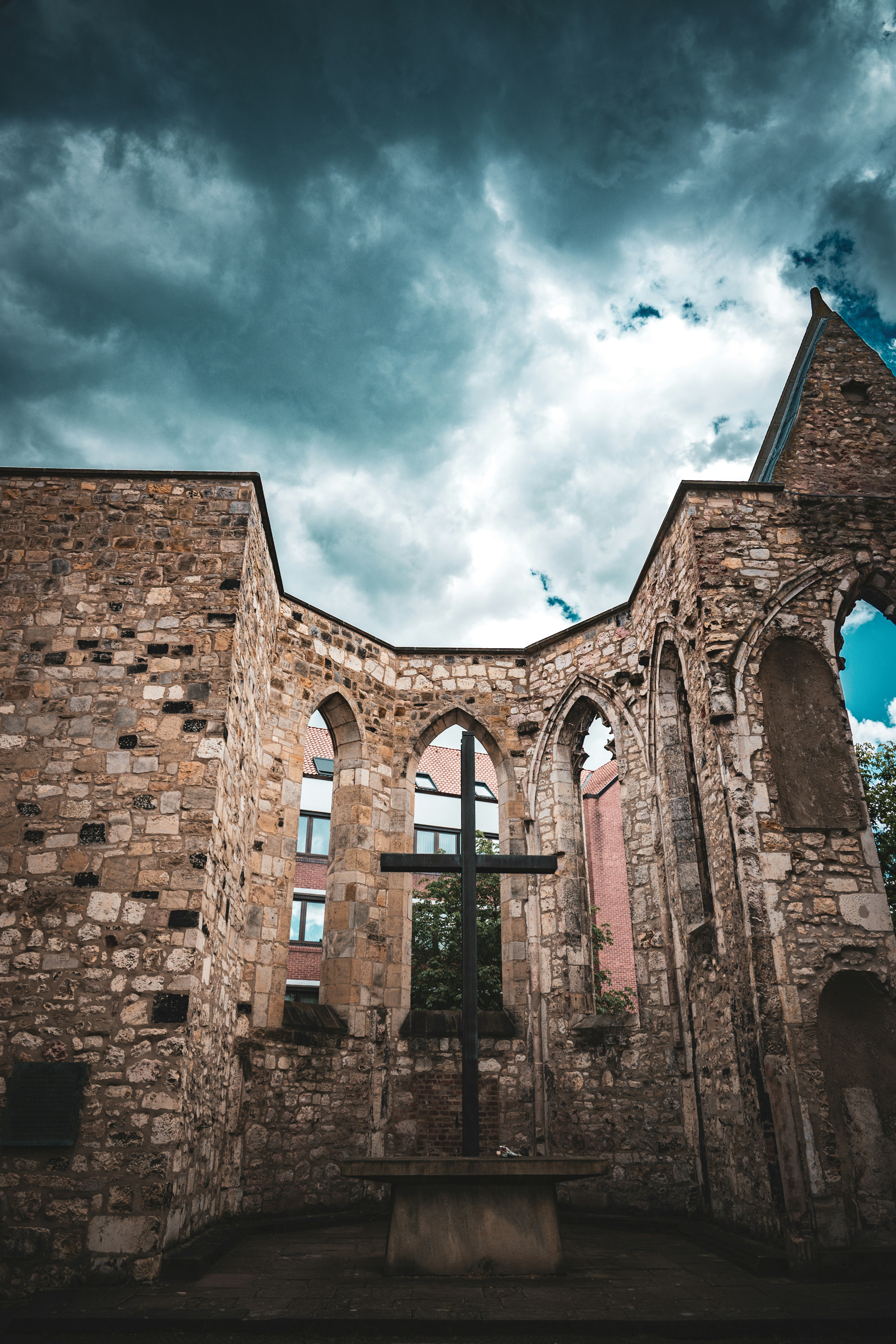 Ancient church ruins with a cross under a dramatic sky