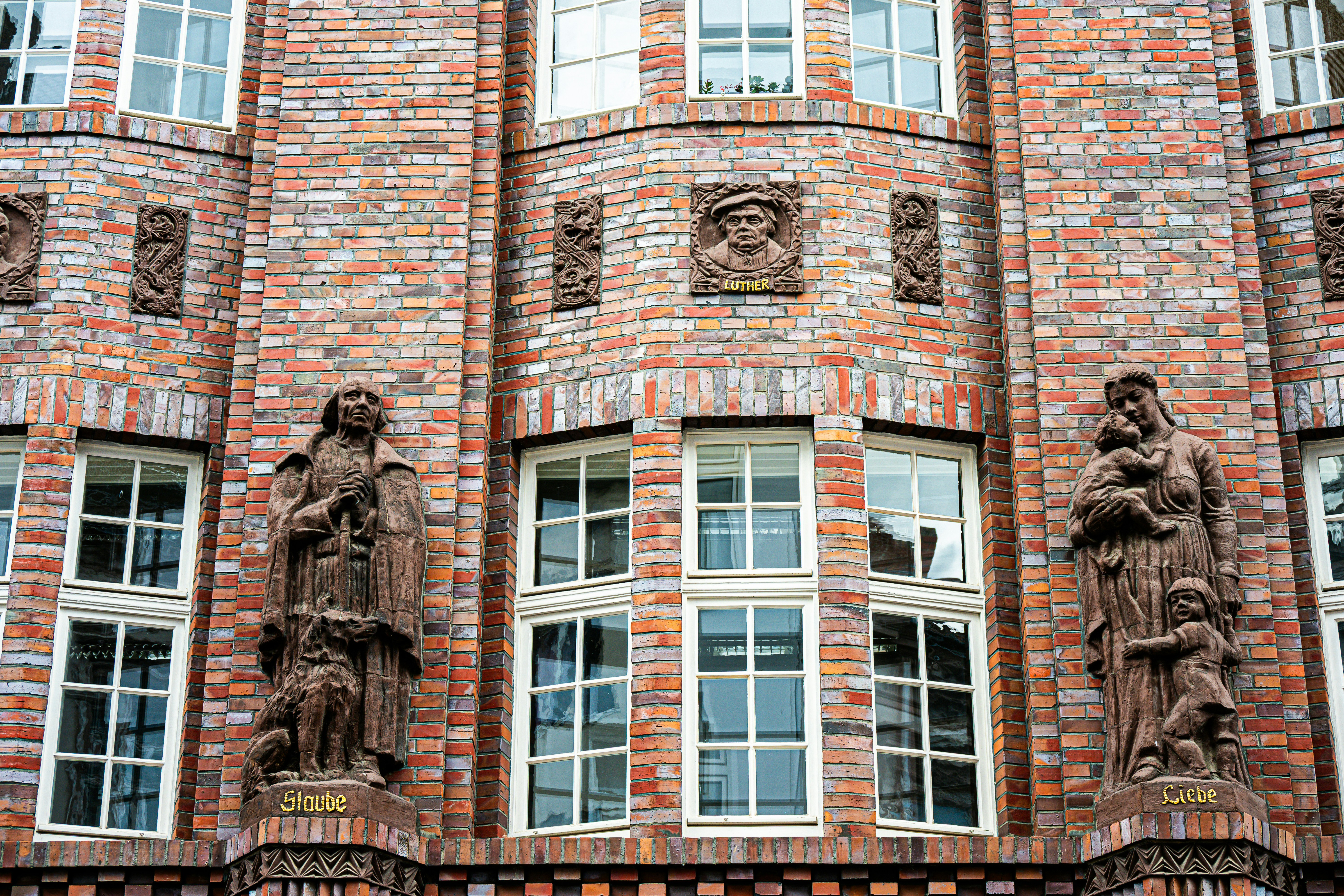Stone Statues Guard a Brick Facade: A Renaissance of Carved Figures Along a Windowed Elevation