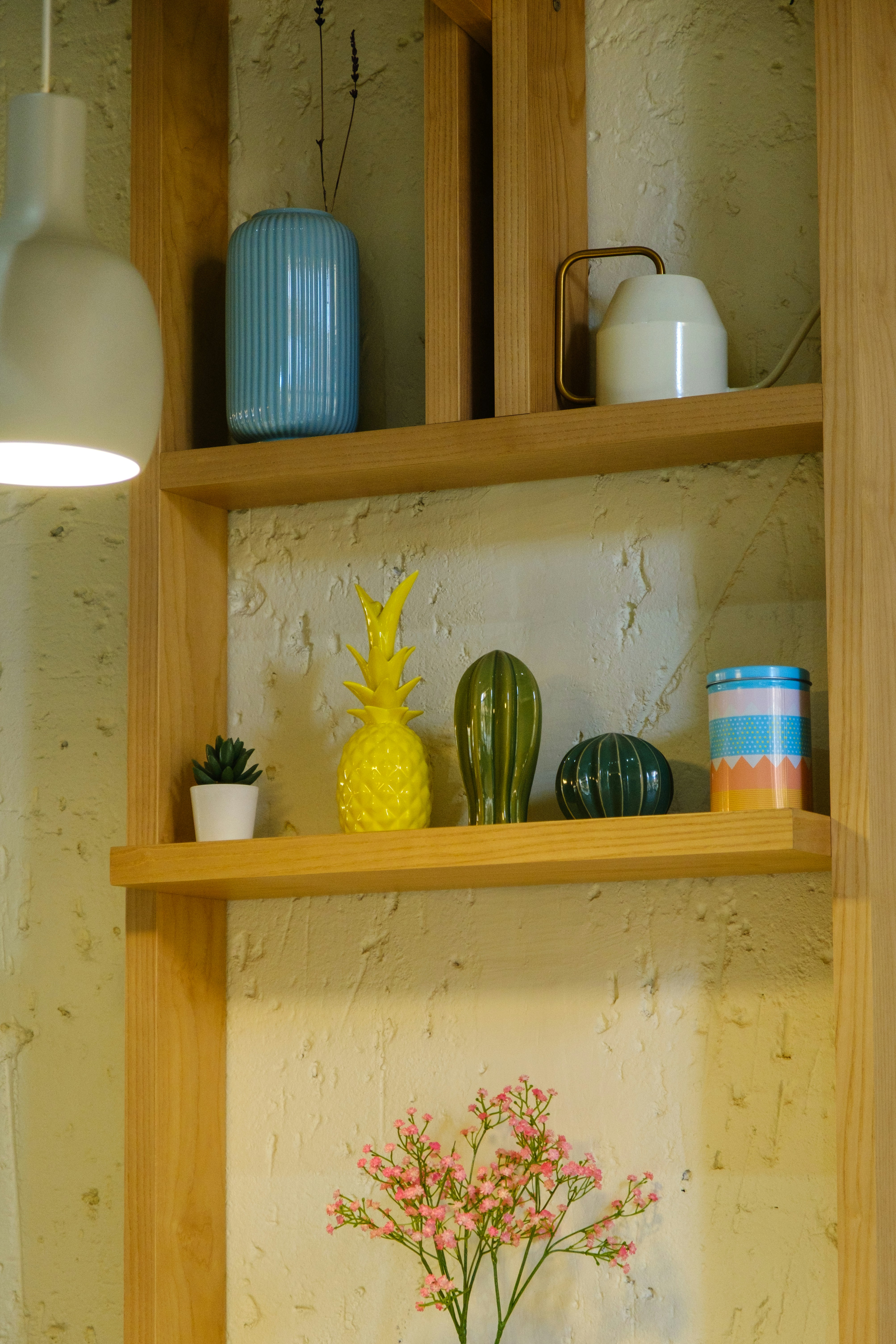 Colorful ceramic vases on a wooden shelf with pink flowering sprigs