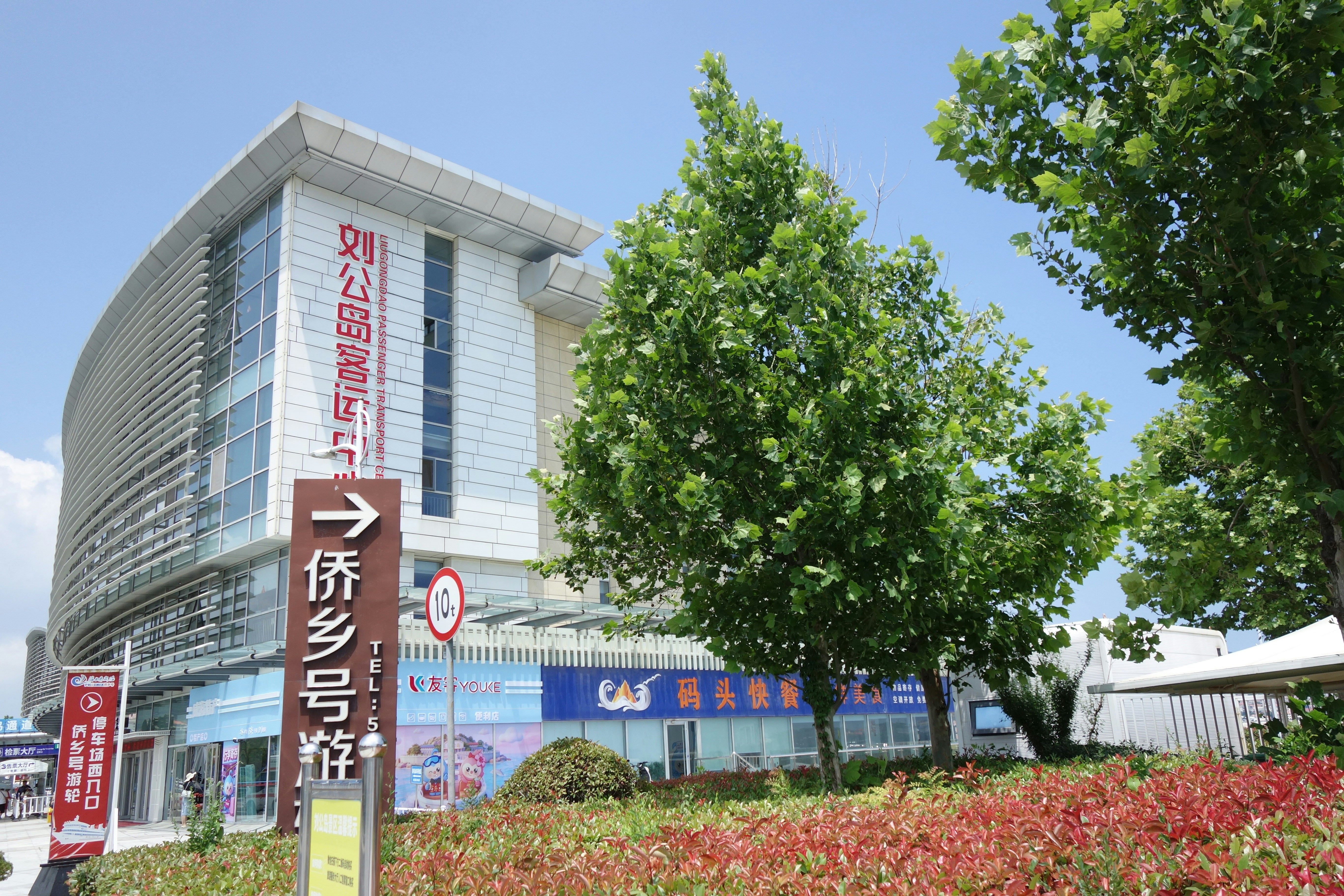 Sunlit Campus Plaza: Modern Building and Lush Trees