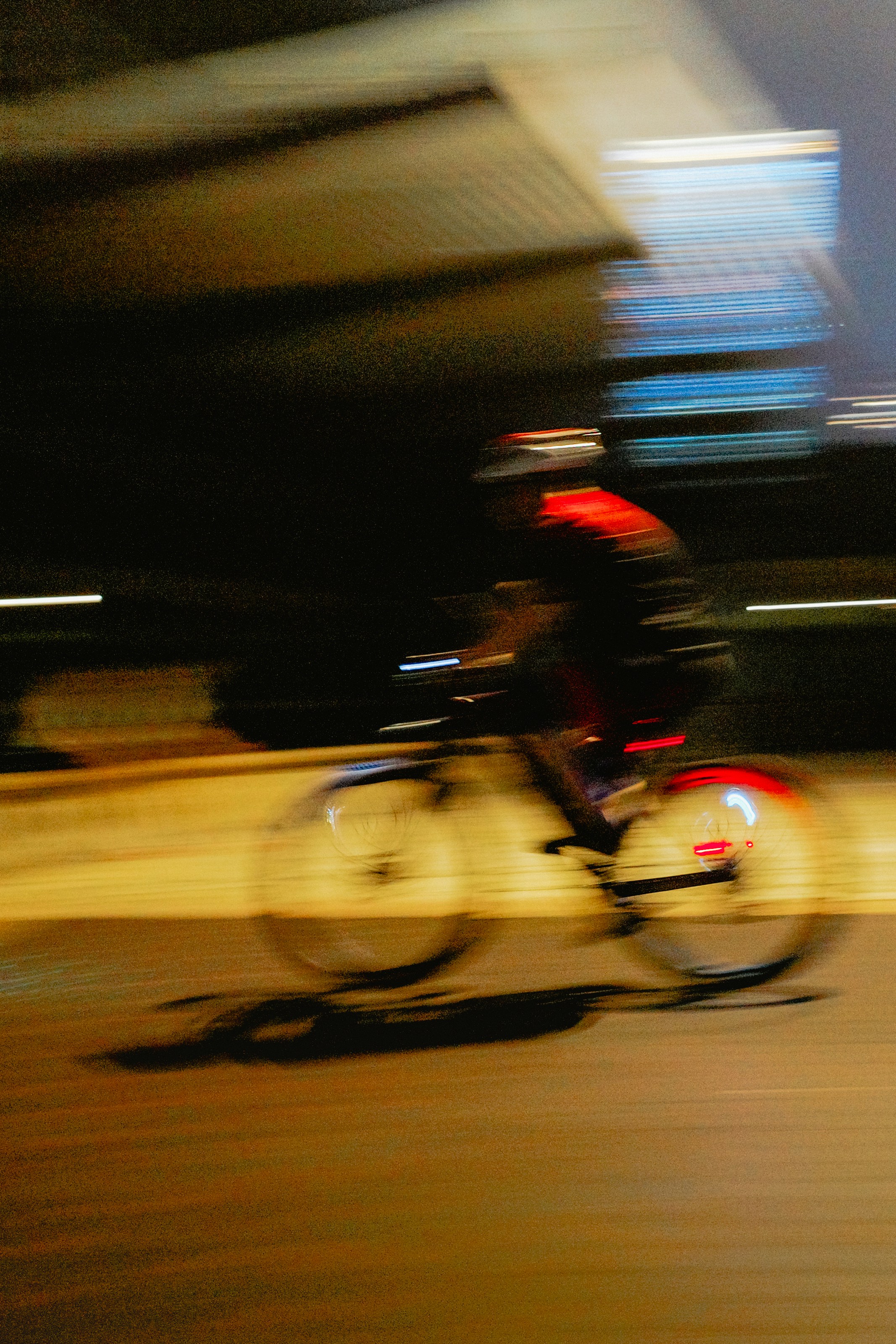 Night Ride in Motion: A Blurred Cyclist Across Urban Lights