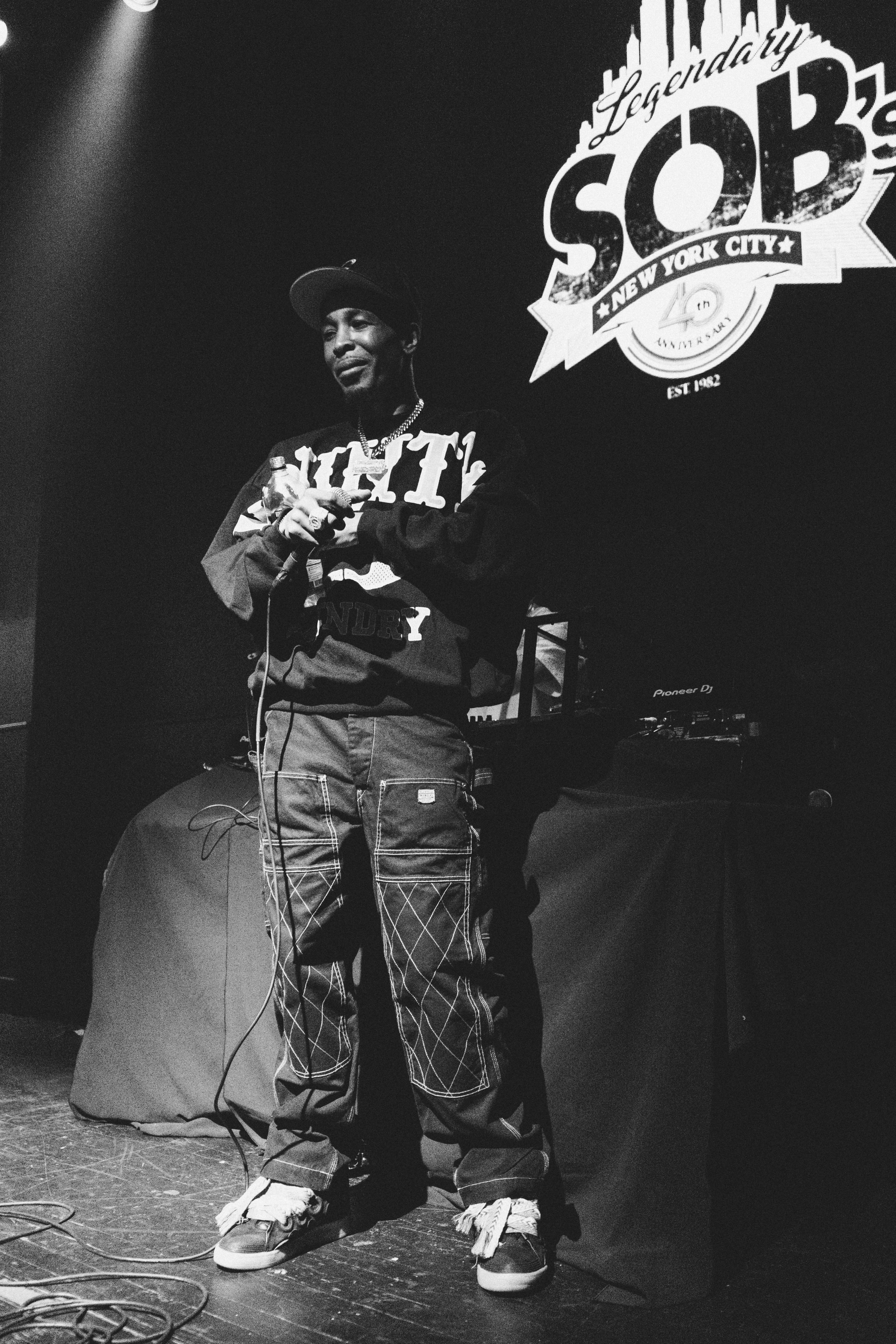 Mid‑Stage Moment: A Rapper Grips the Mic Under Club Lights