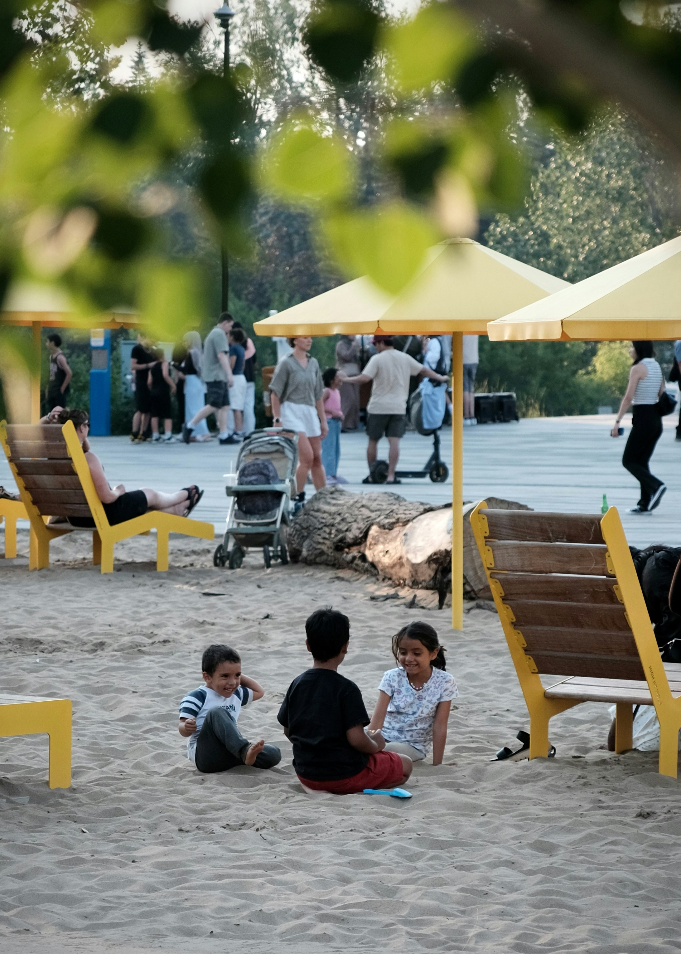 Sunlit Sand Chorus: Kids Gather Near Yellow Loungers Under Parasol Shade