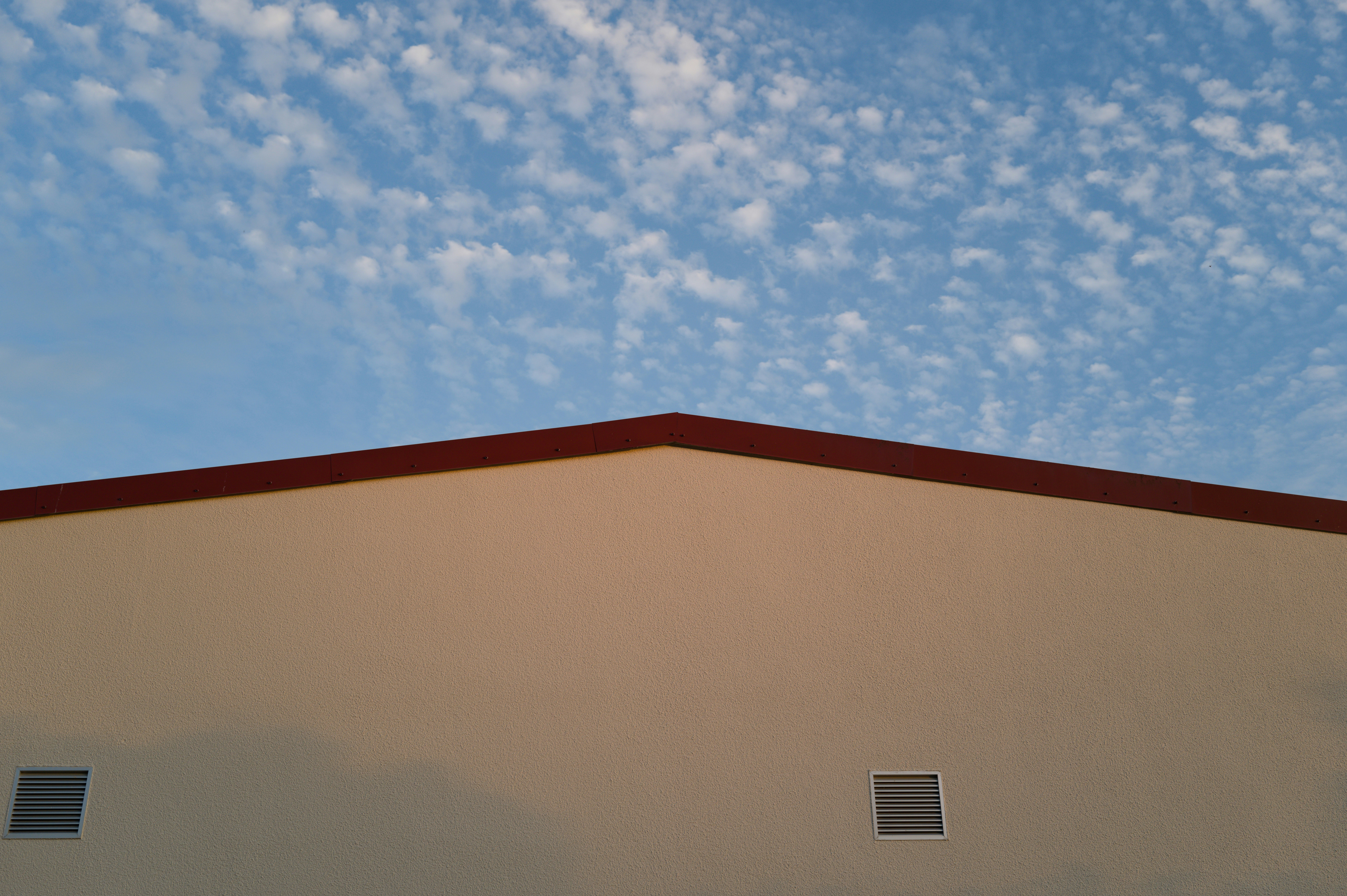 Sunlit Ridge: Minimalist Facade Under a Patchwork Sky
